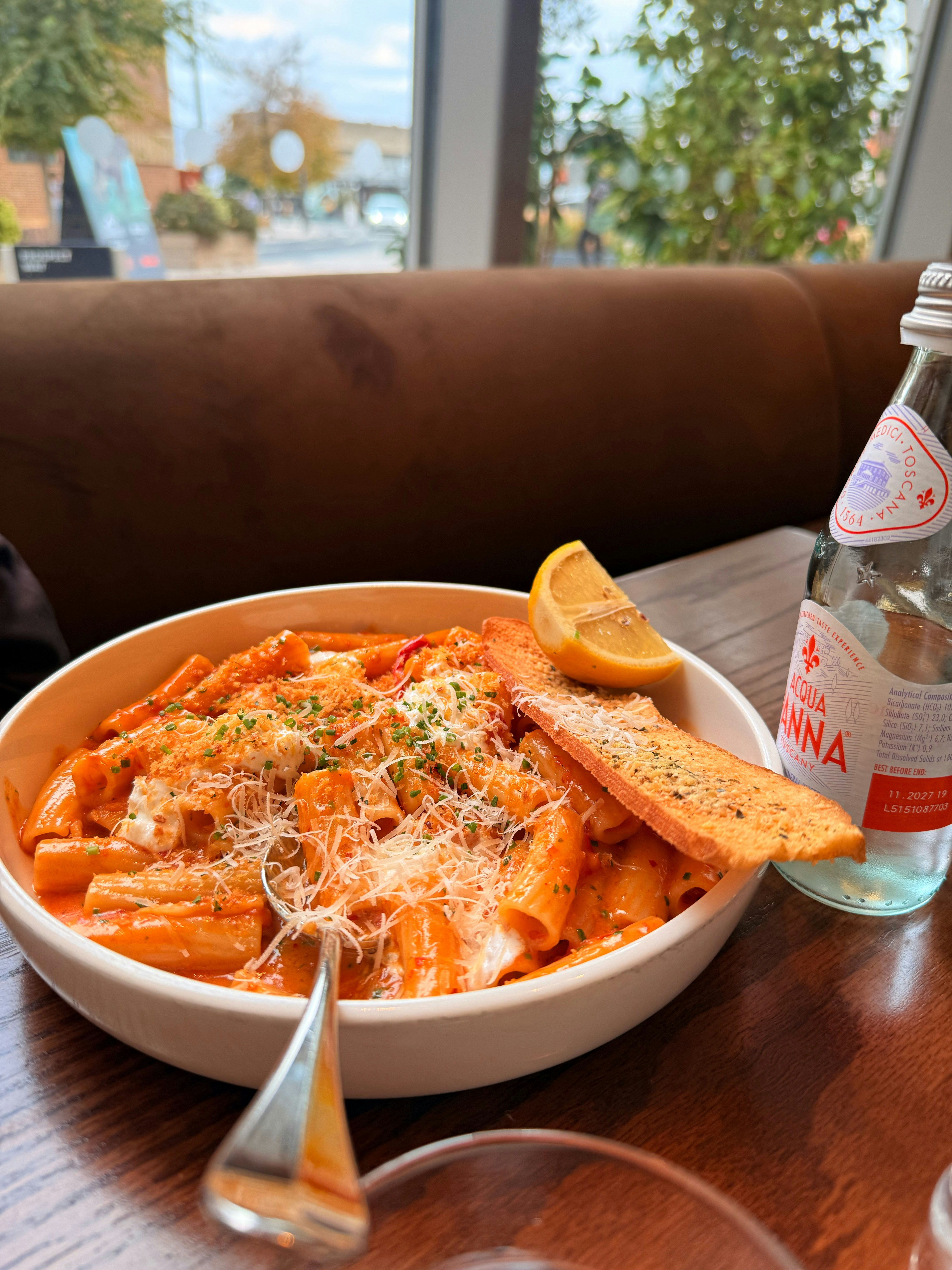 Creamy Pasta in a Cozy Café, Toast and Sparkling Water on the Table