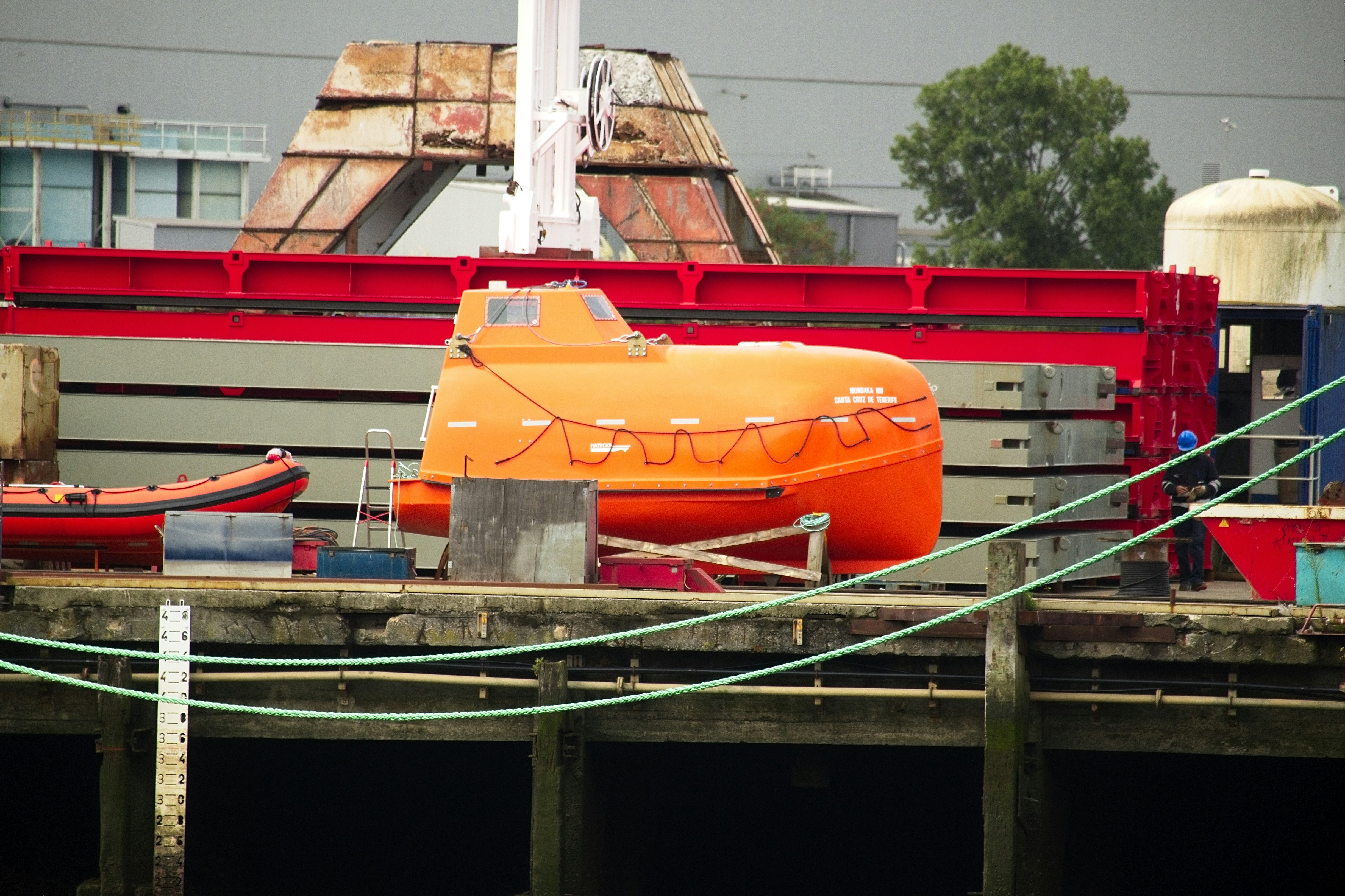 Orange Lifeboat on a Dock Amid Industrial Structures