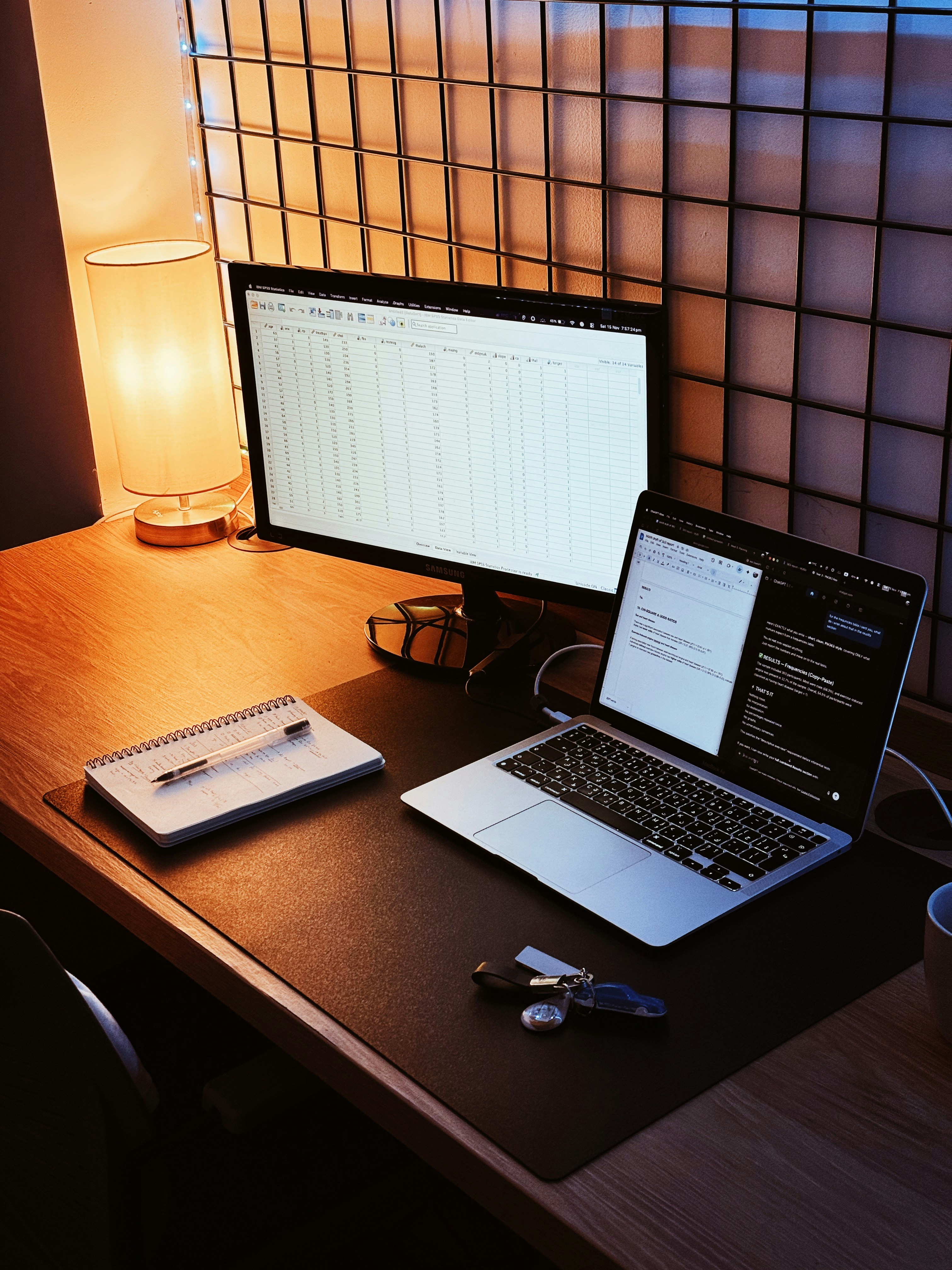 Dual-Screen Workspace: Monitors, Laptop, and Keys on a Wooden Desk