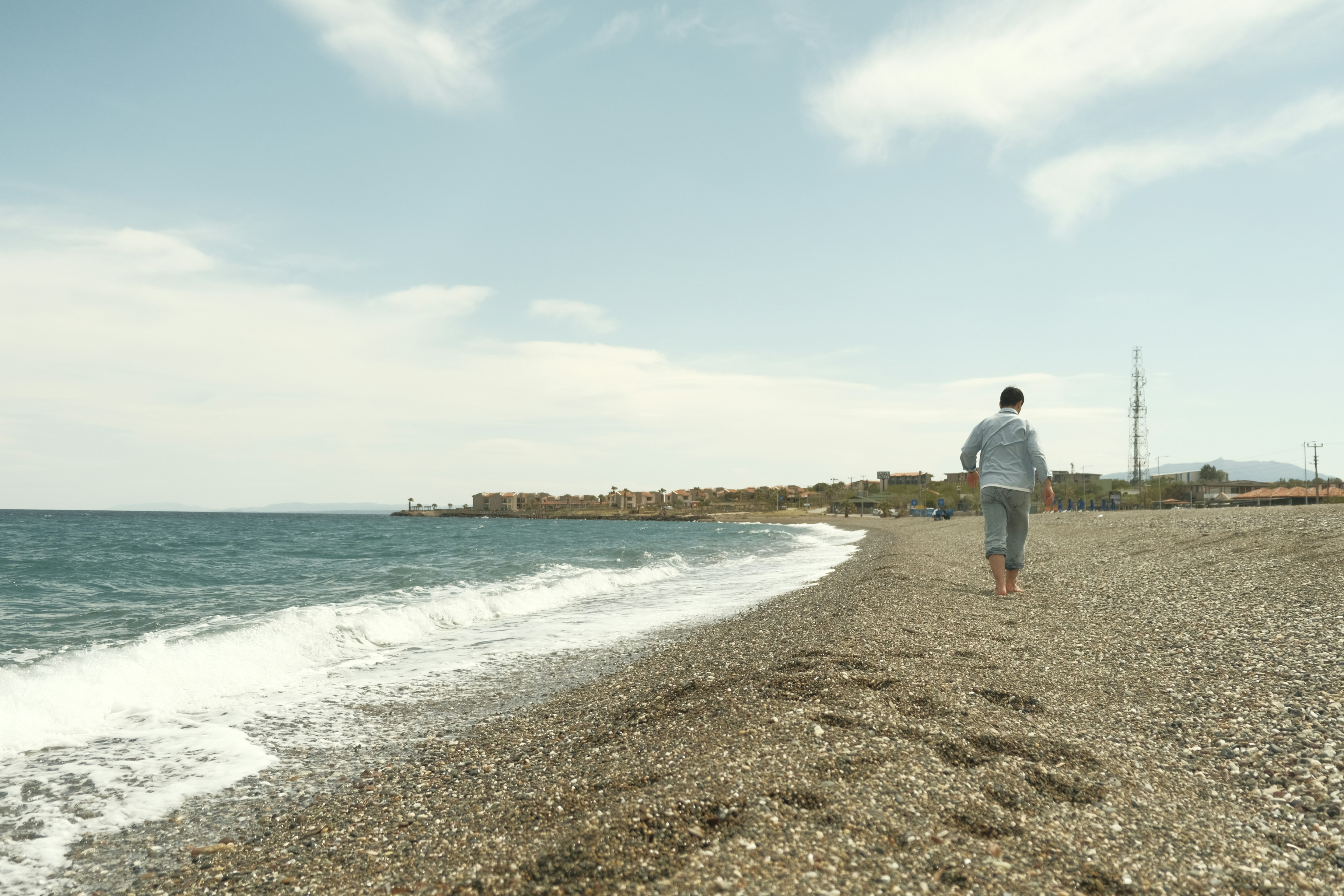 Coastal Wanderer: A solitary figure along a pebbled shoreline