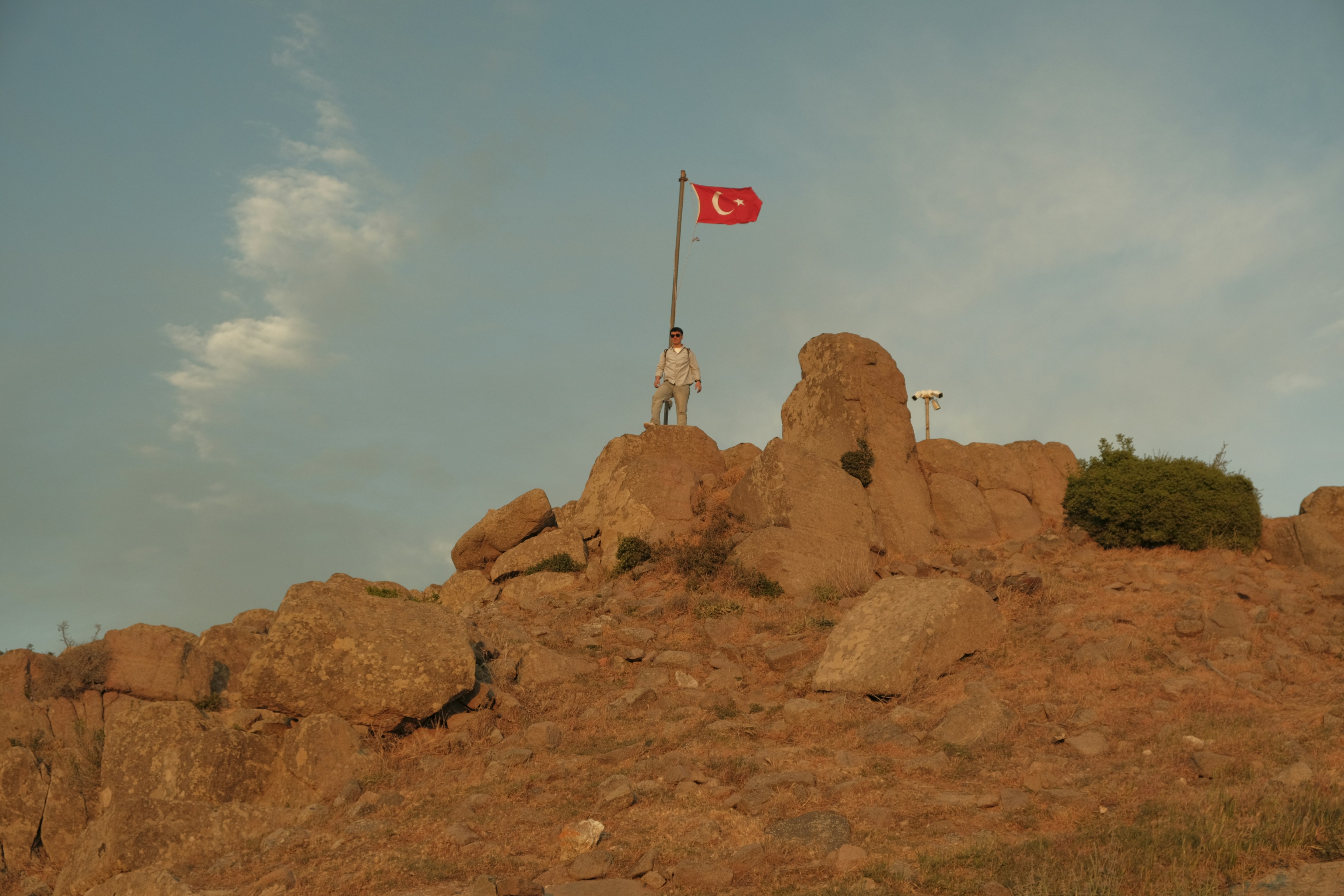 Turkish Flag atop a rocky outcrop: lone figure guarding the summit