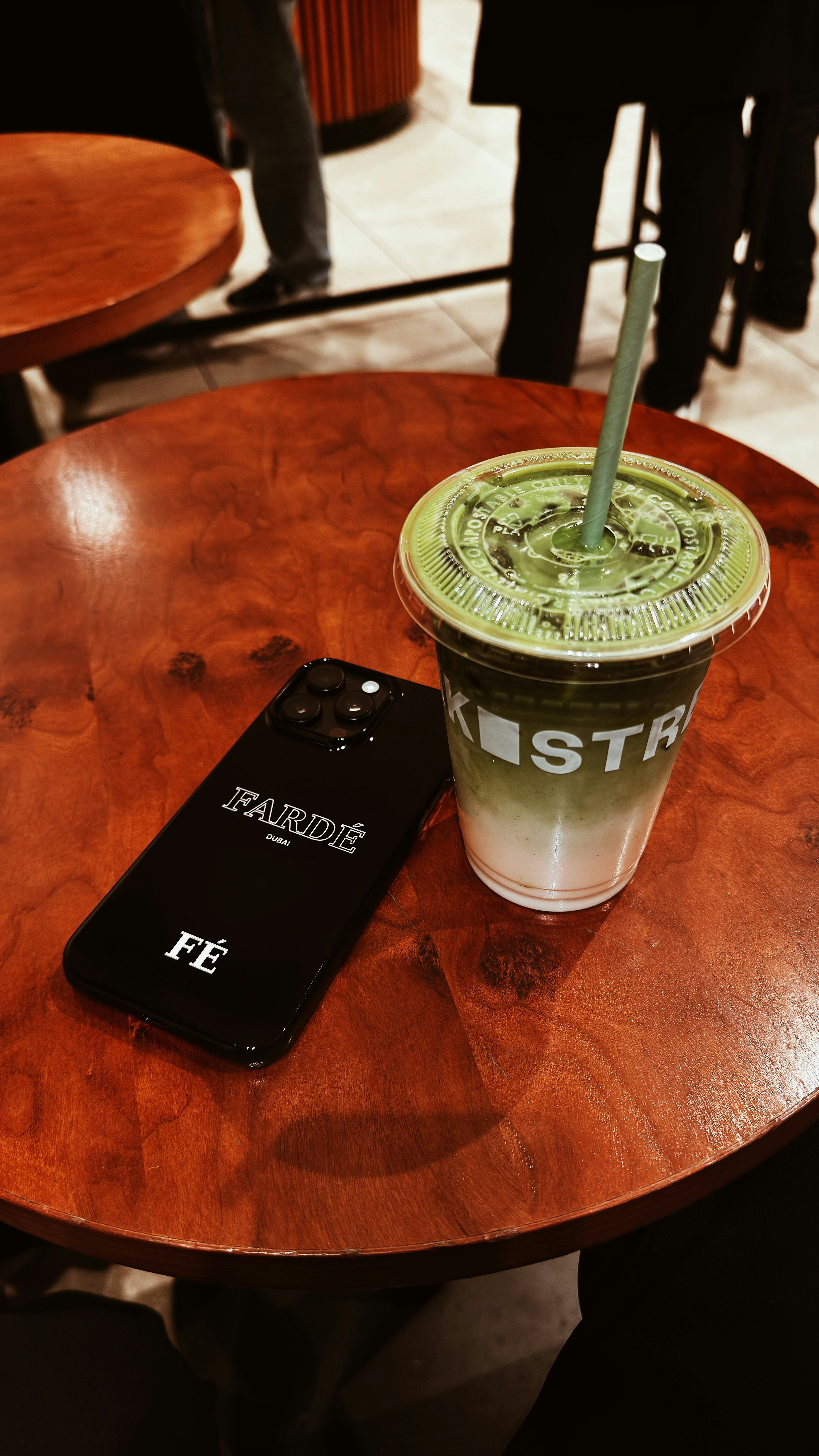 Green-terraiced drink and glossy iPhone on a cafe table