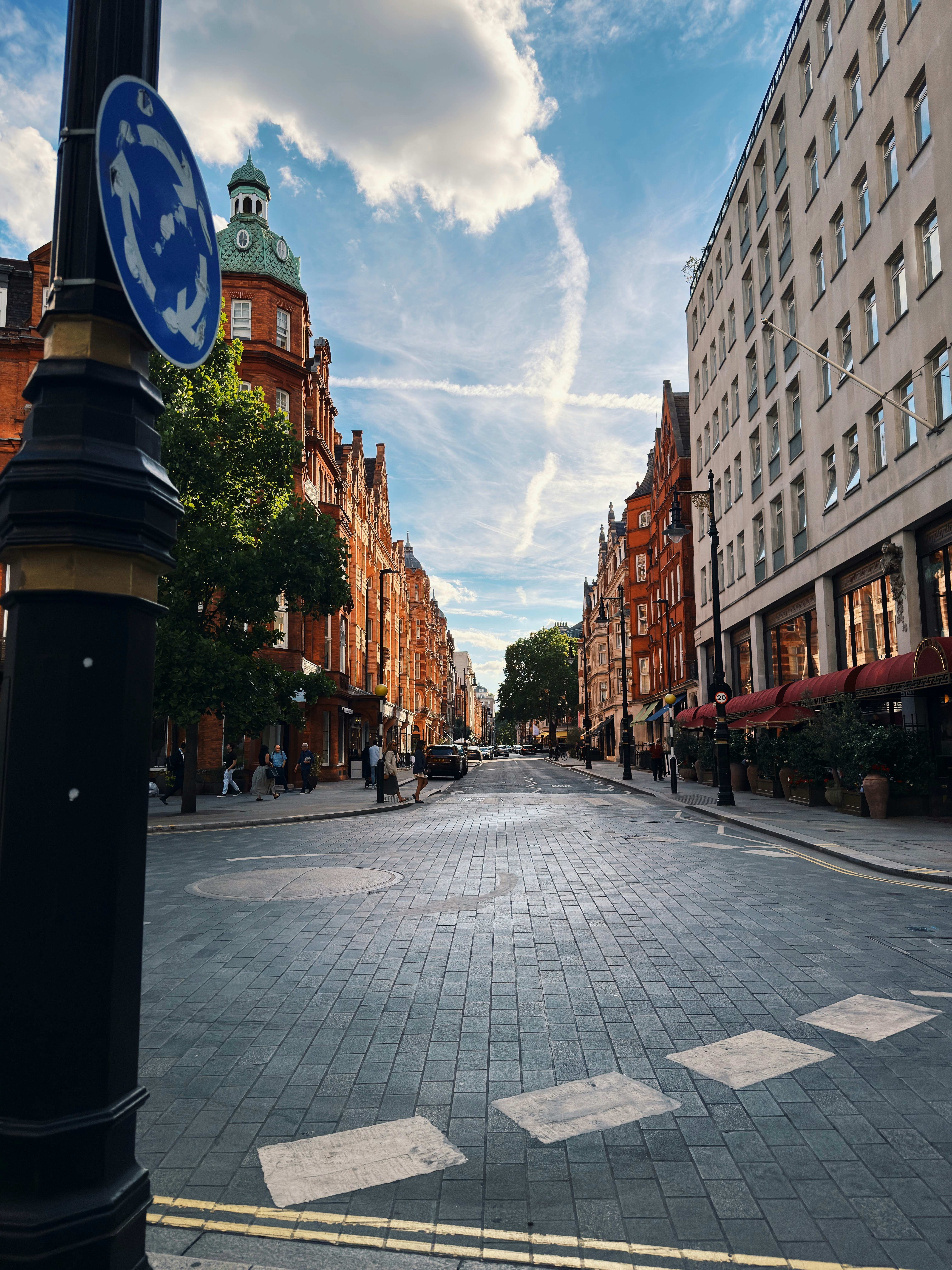 A Sunlit City Street: Red Bricks, Modern Facades, and a Looming Blue Sky