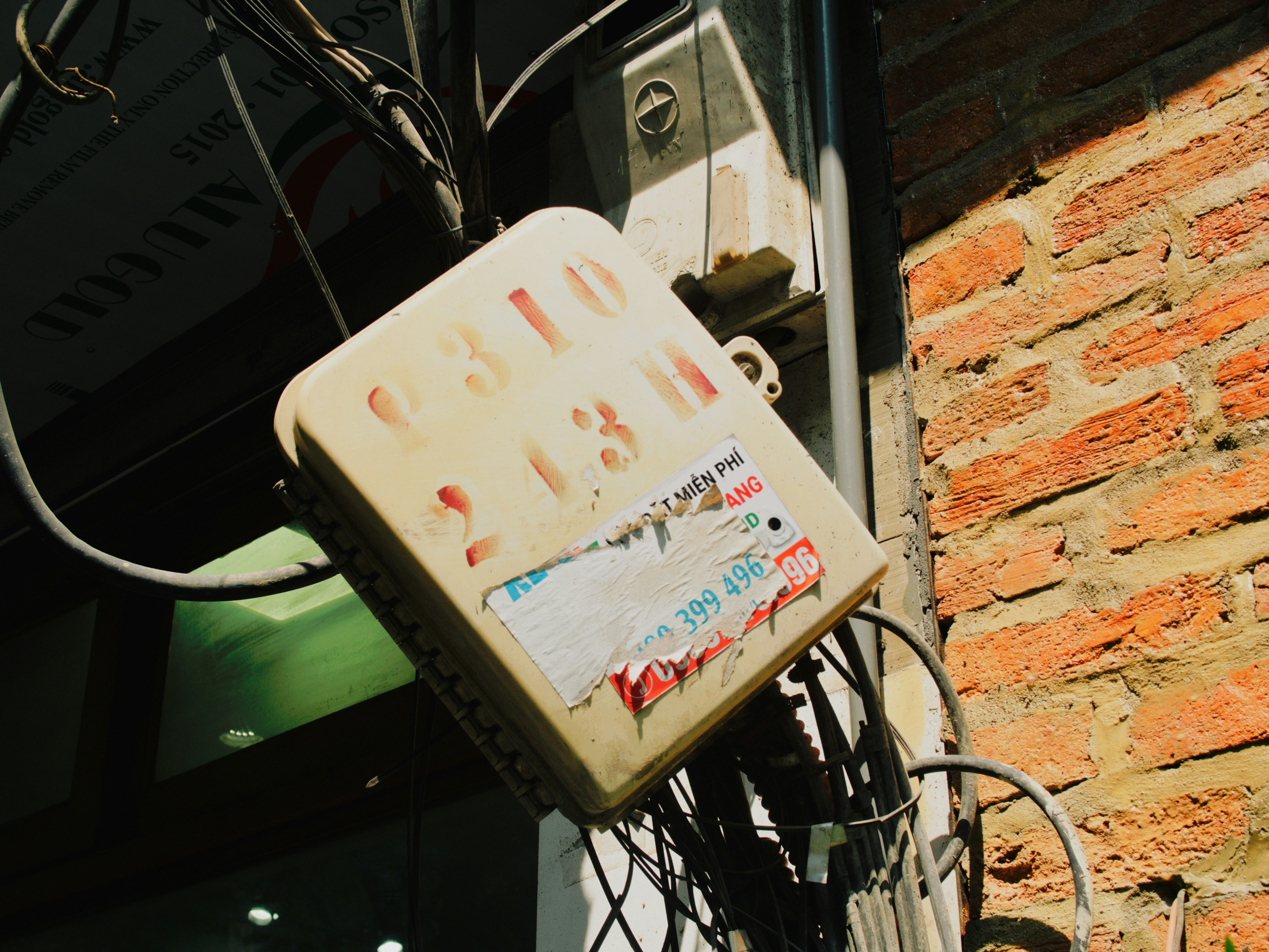 Wires and a Weathered Outlet: Urban Entanglement Near Brick Facade