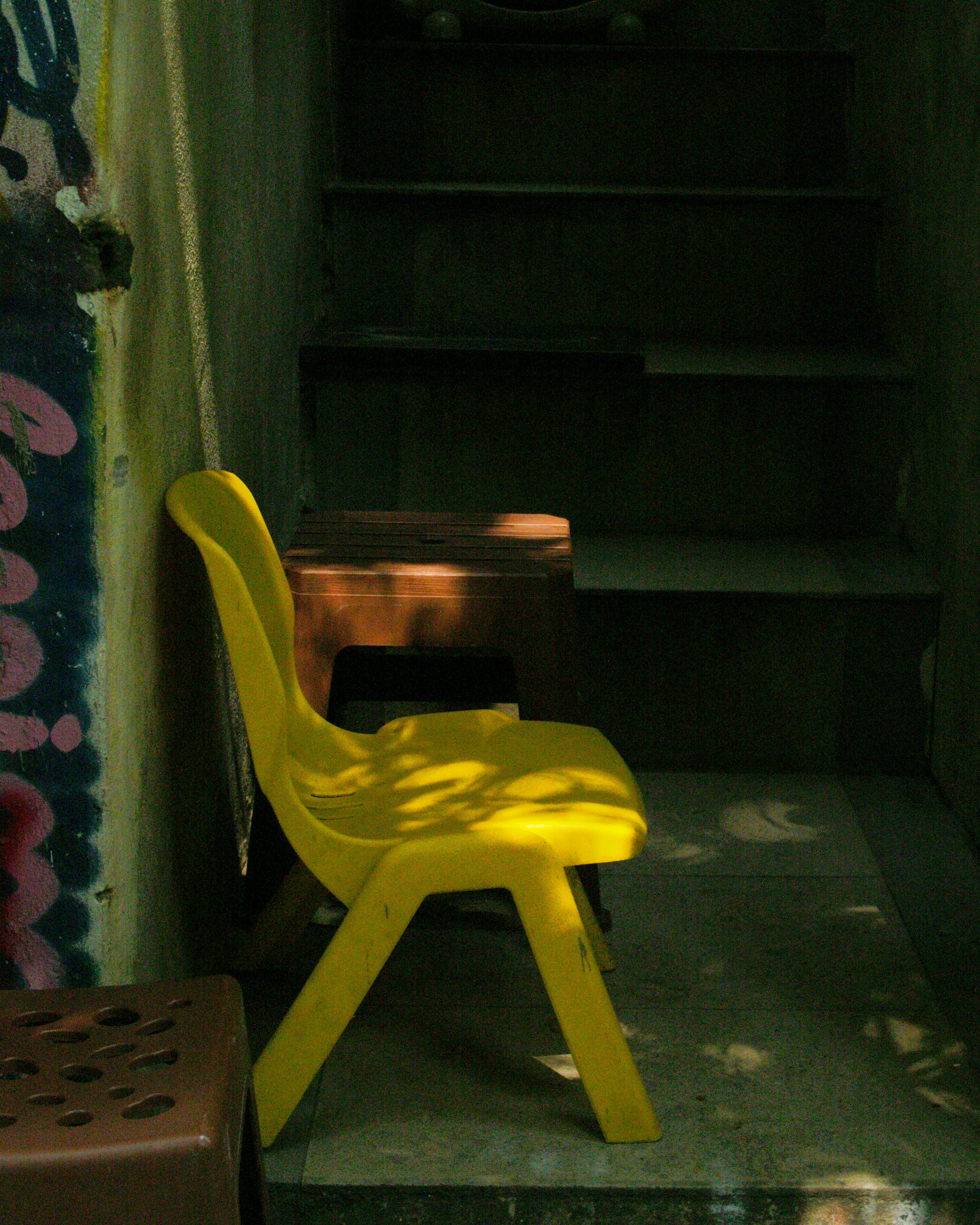 Yellow Chair at the Foot of a Dim Staircase