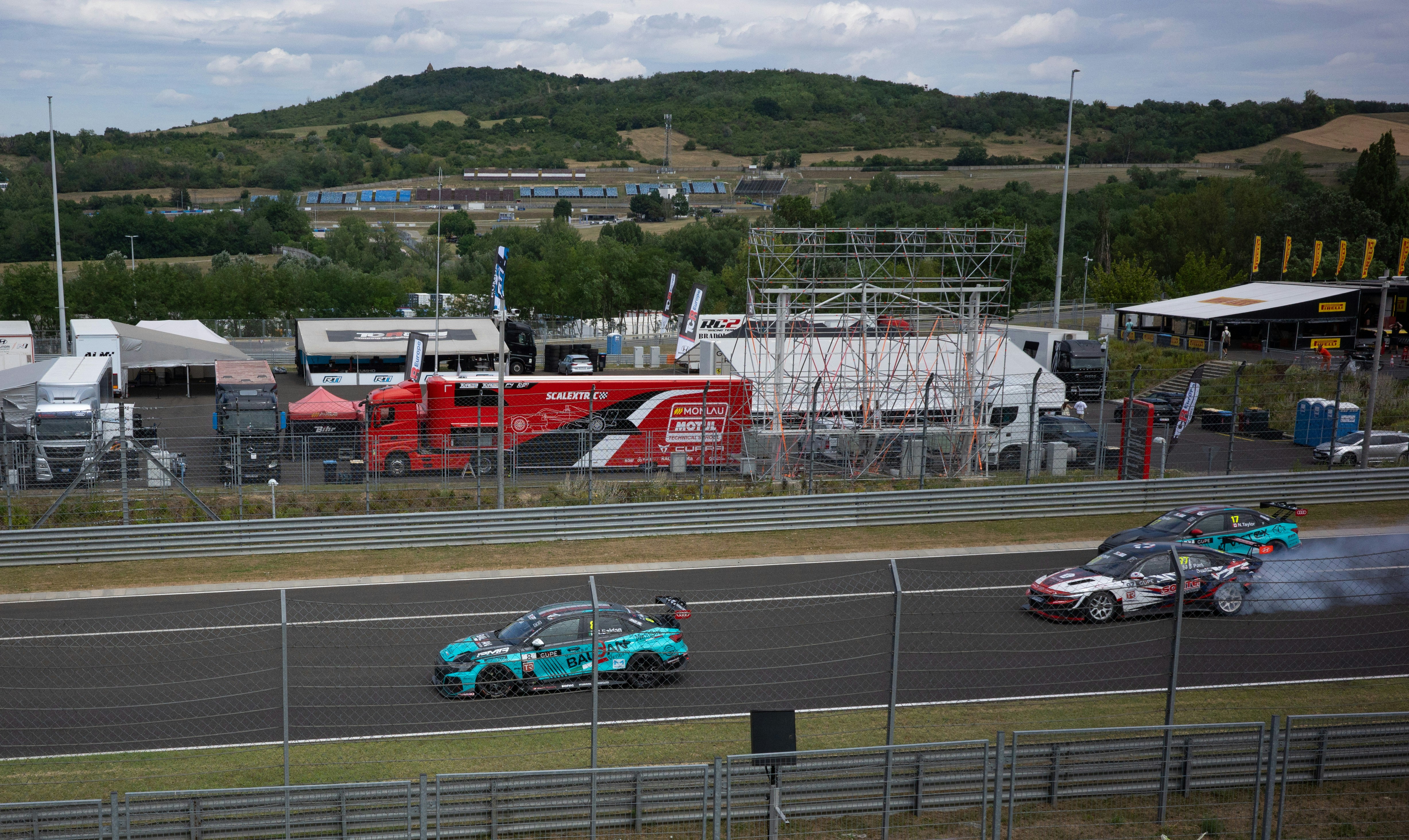 Racing in the paddock: teal car leads a tight pack on the track