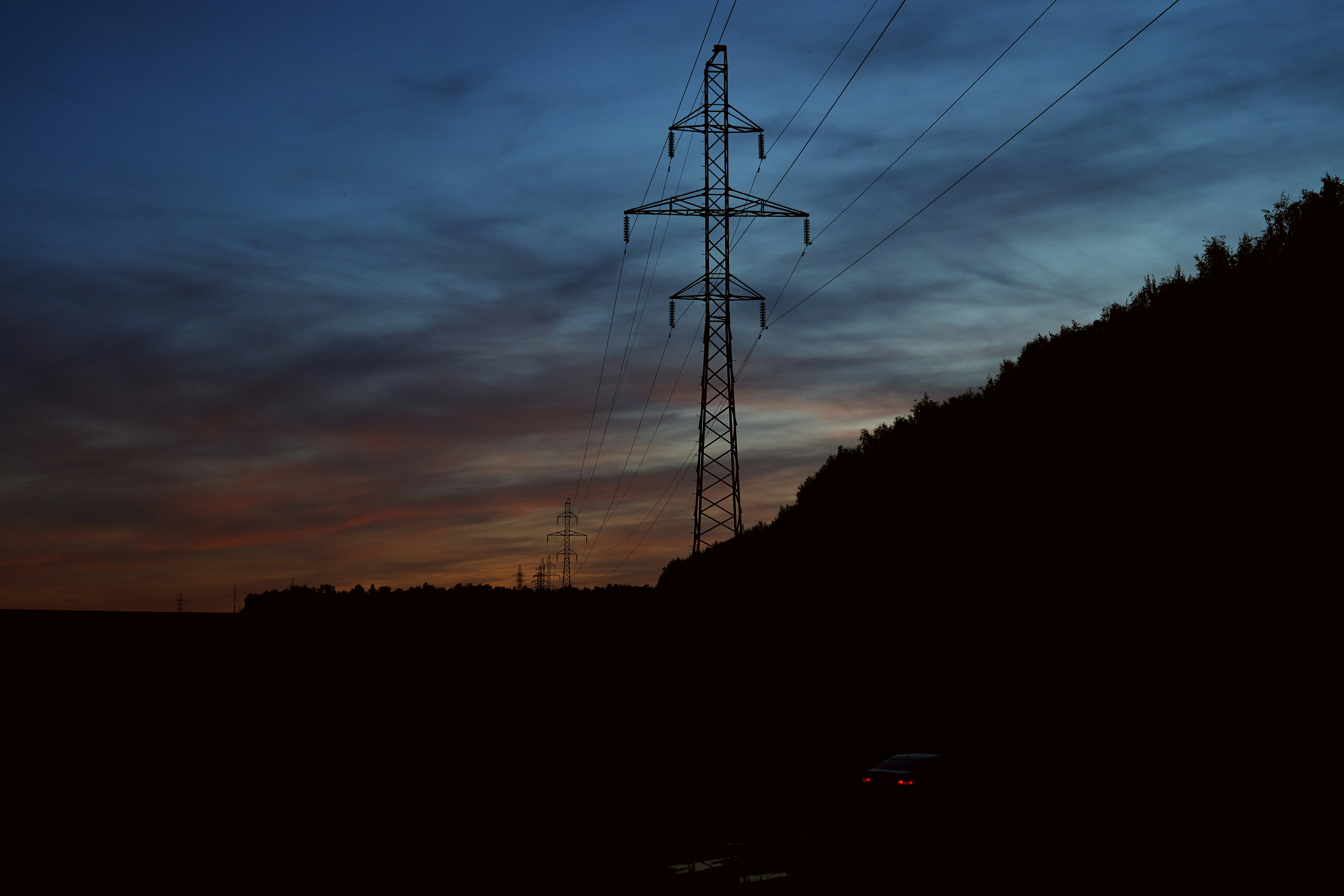 Silhouetted Tower at Dusk: Power Lines Crossing a Quiet Horizon