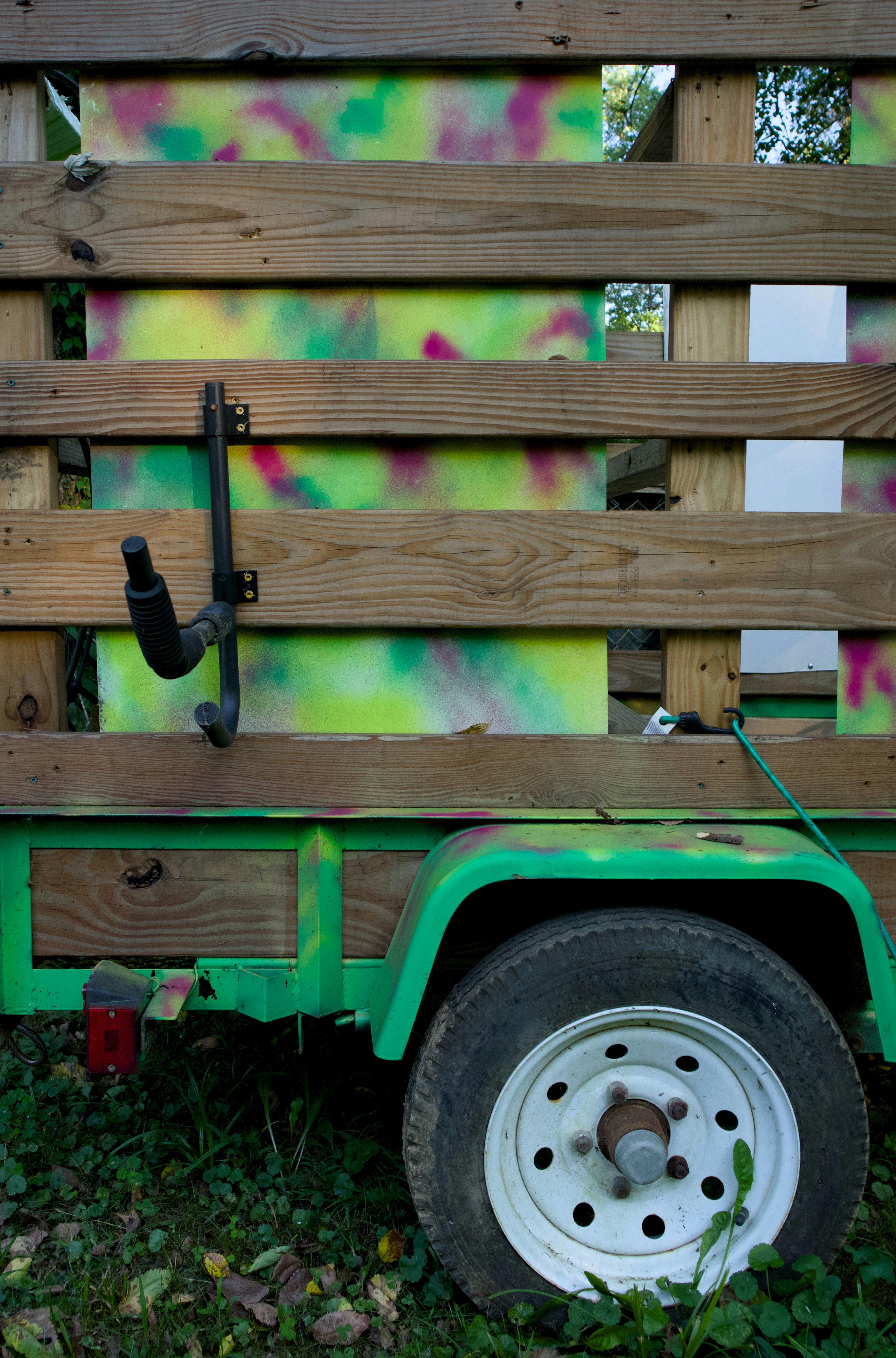 Green Trailing: A Rustic Trailer with Neon Tie-dye and Worn Wheels