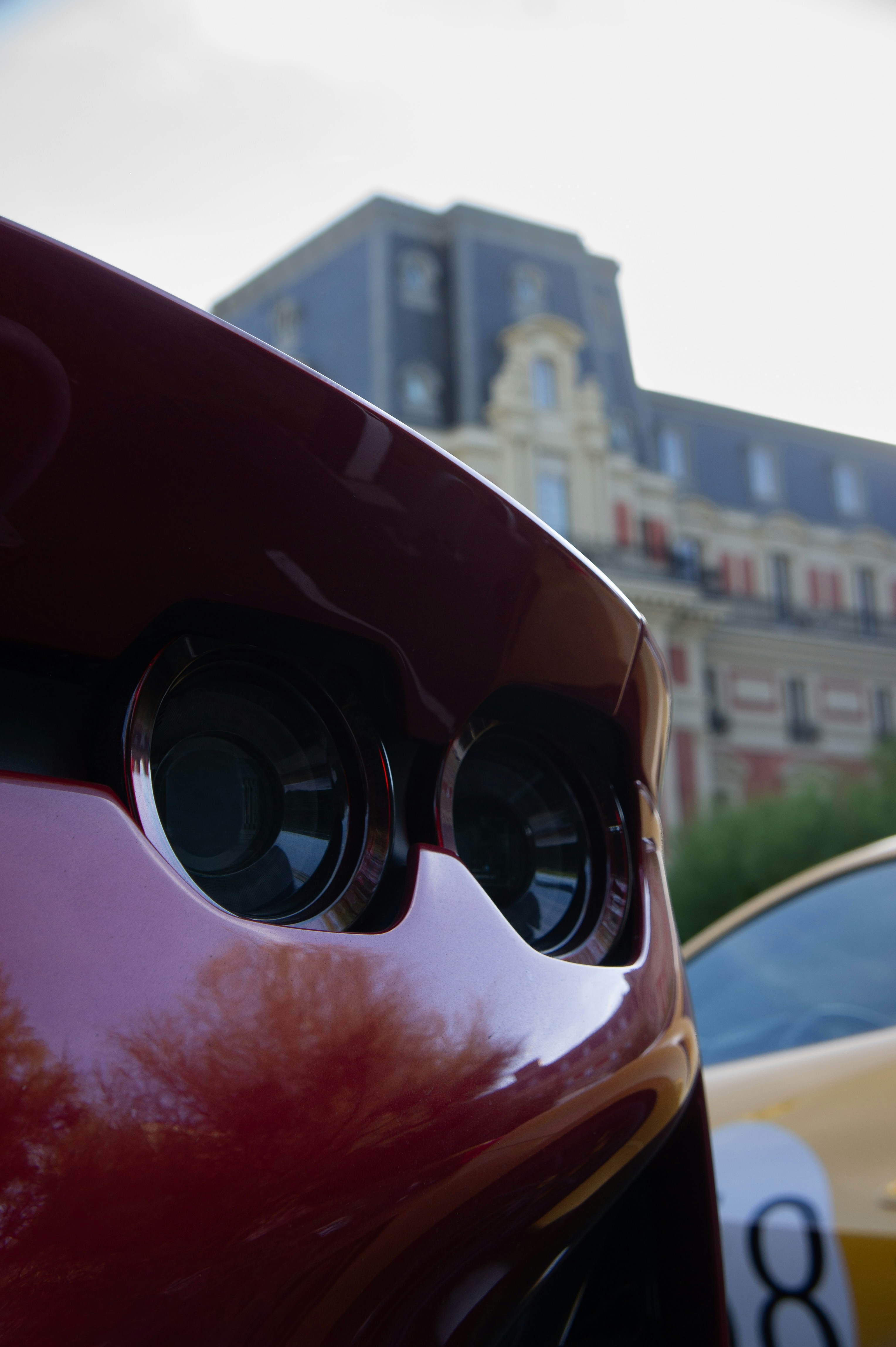 Gazing Red: A Car's Headlight Gaze Framed by Urban Backdrop