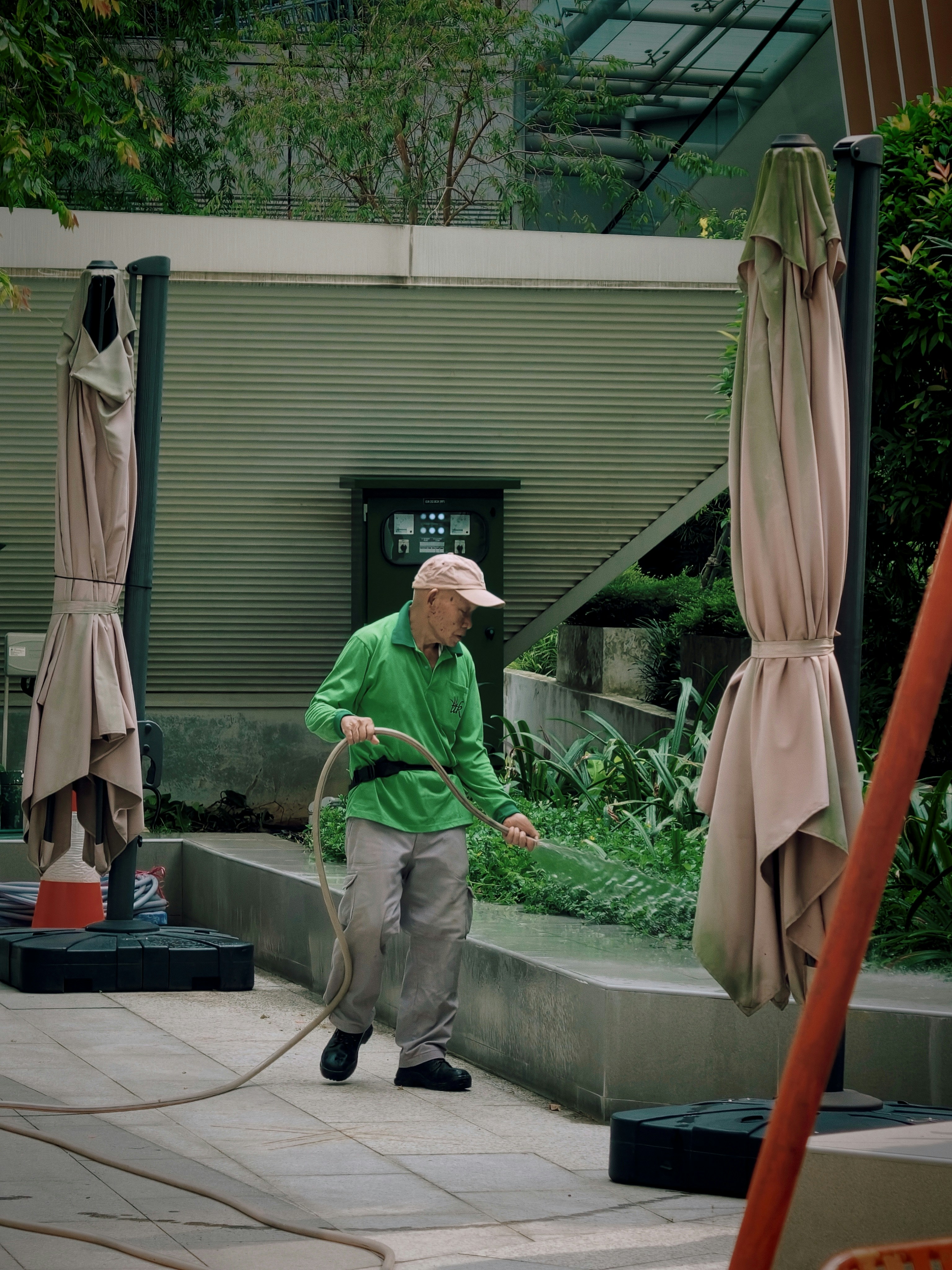 Green-vested Gardener with Hose in Urban Courtyard