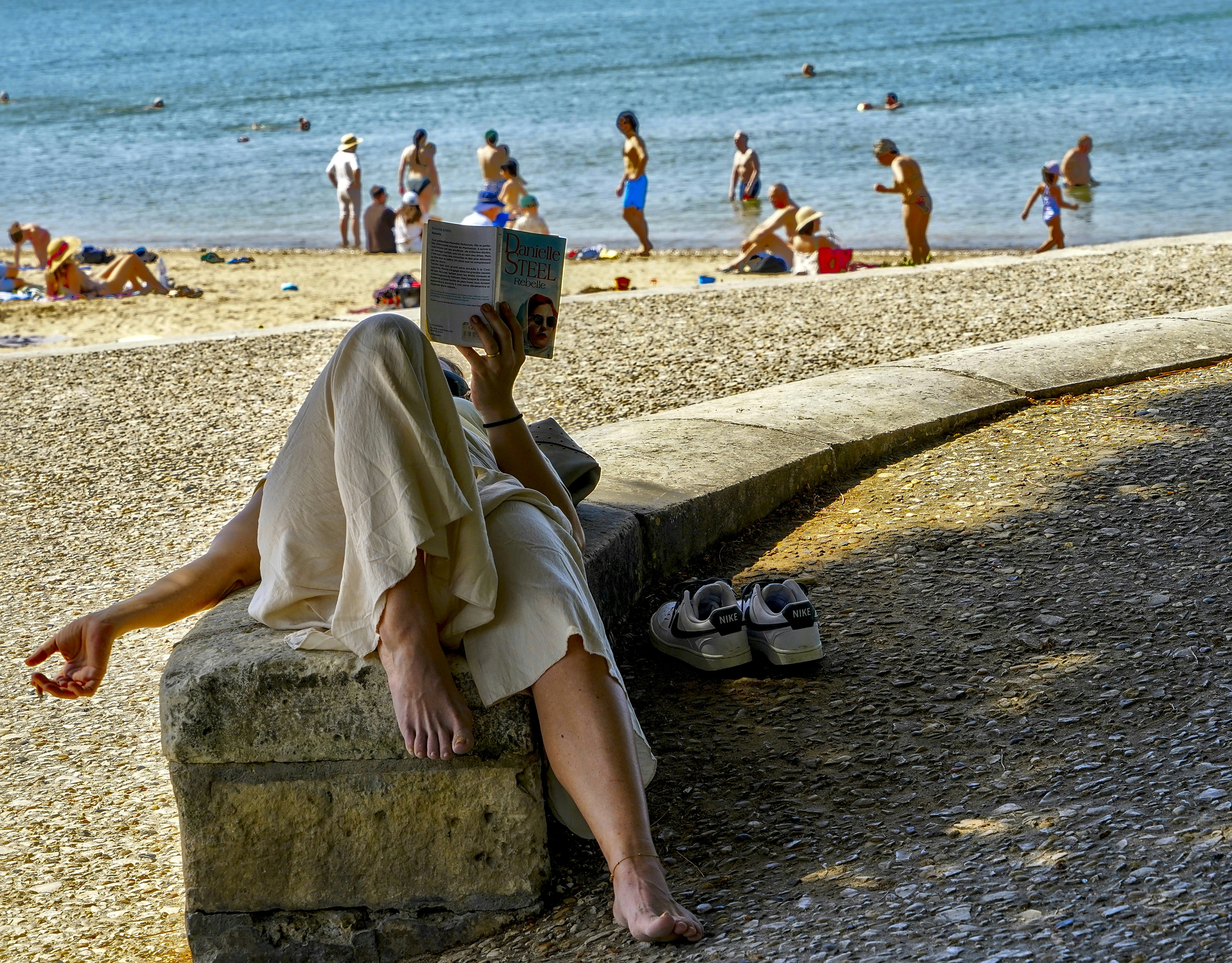 Reading Ritual by the Sea: A Traveler's Quiet Break on the Pebbled Promenade