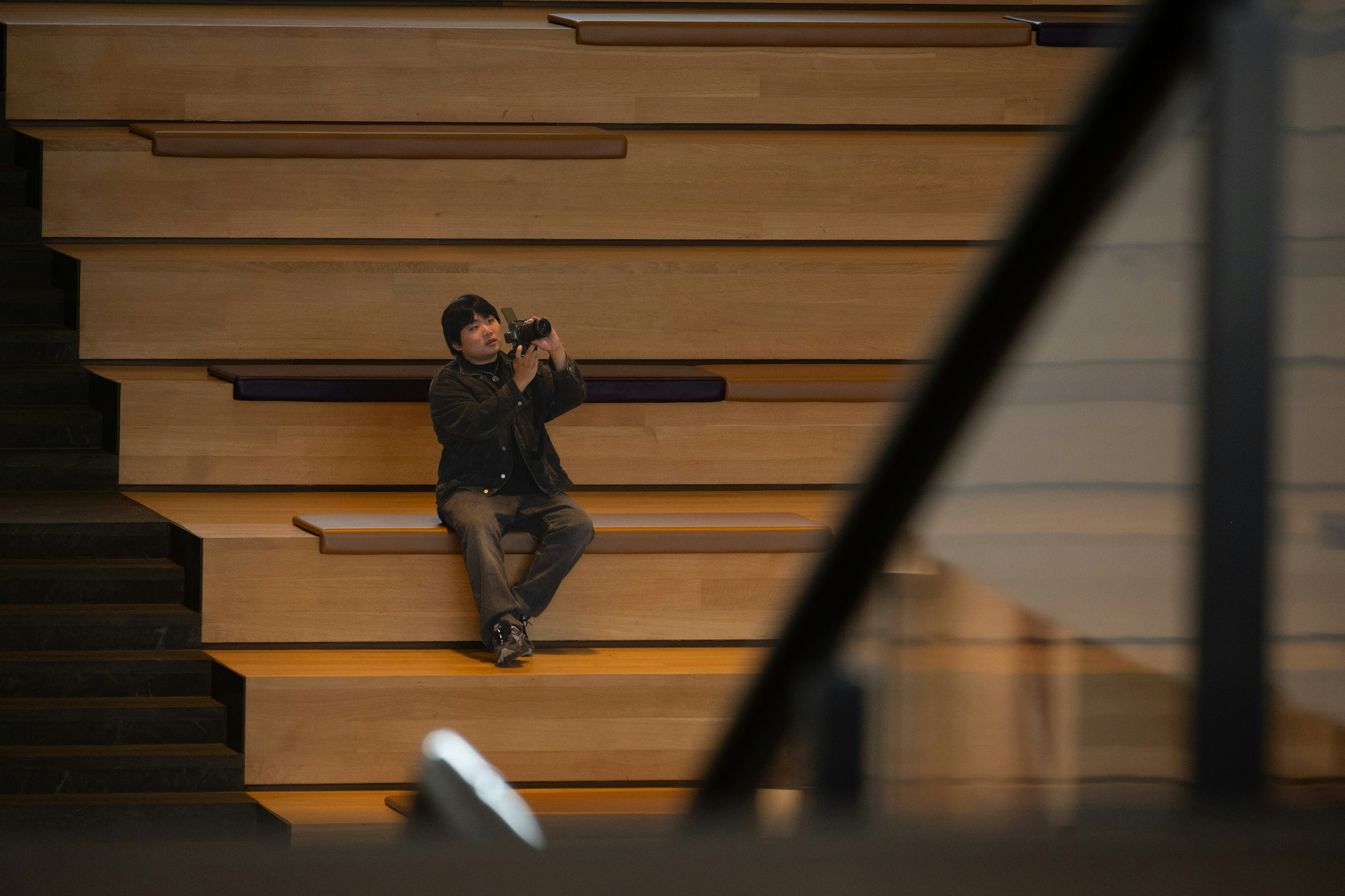 Photographer on wooden amphitheater steps steadies a camera for a candid shot