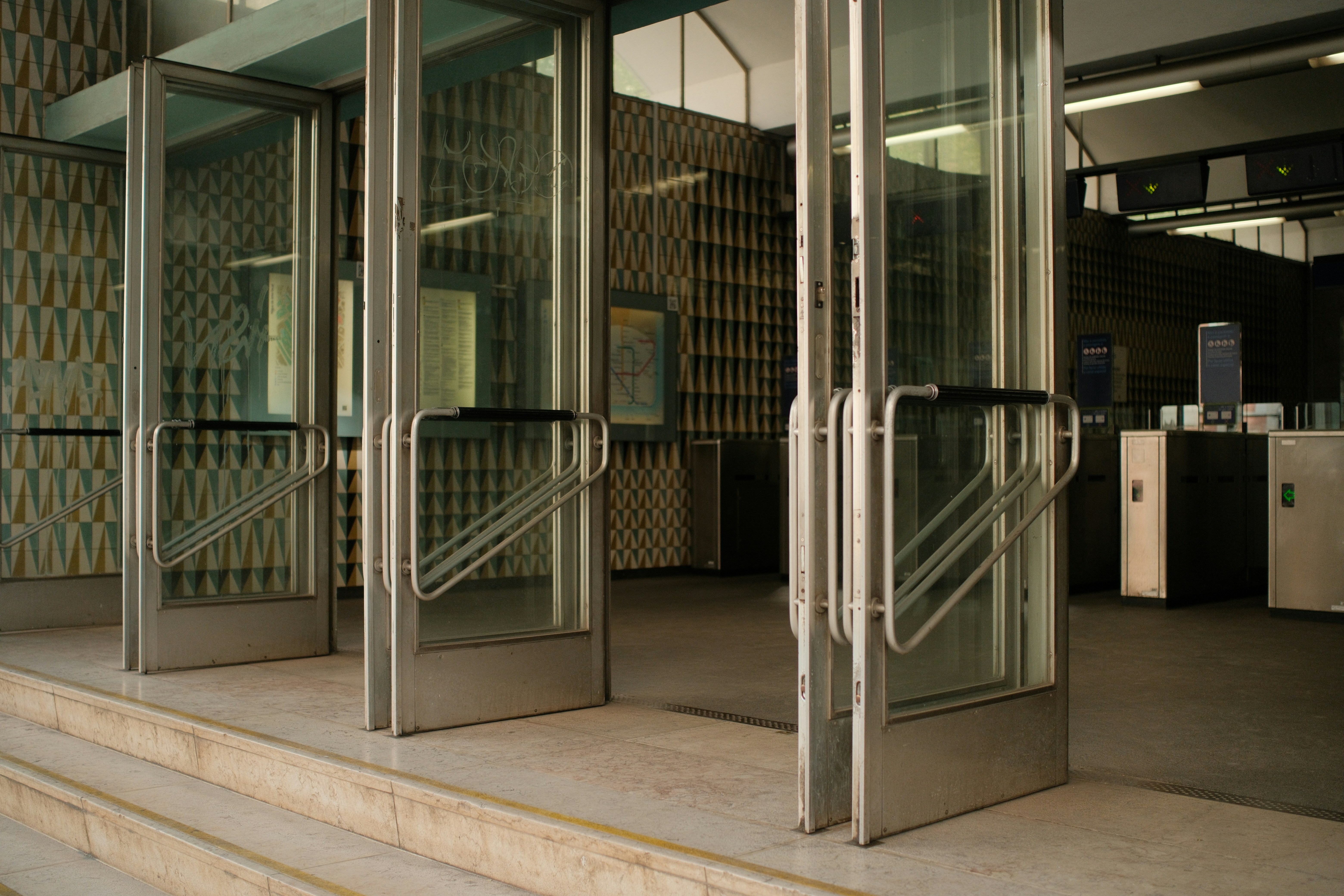 Glass entrance doors and geometric tiled walls at Parque station on the Lisbon Metro, showing the characteristic design of the underground transport network. Lisbon, Portugal, August 2025. Captured with Fujifilm X-M5 and Viltrox 25/1.7 // Portas de vidro e paredes revestidas com padrões geométricos na estação Parque do Metro de Lisboa, mostrando o design característico da rede de transporte subterrâneo. Lisboa, Portugal, agosto de 2025.
