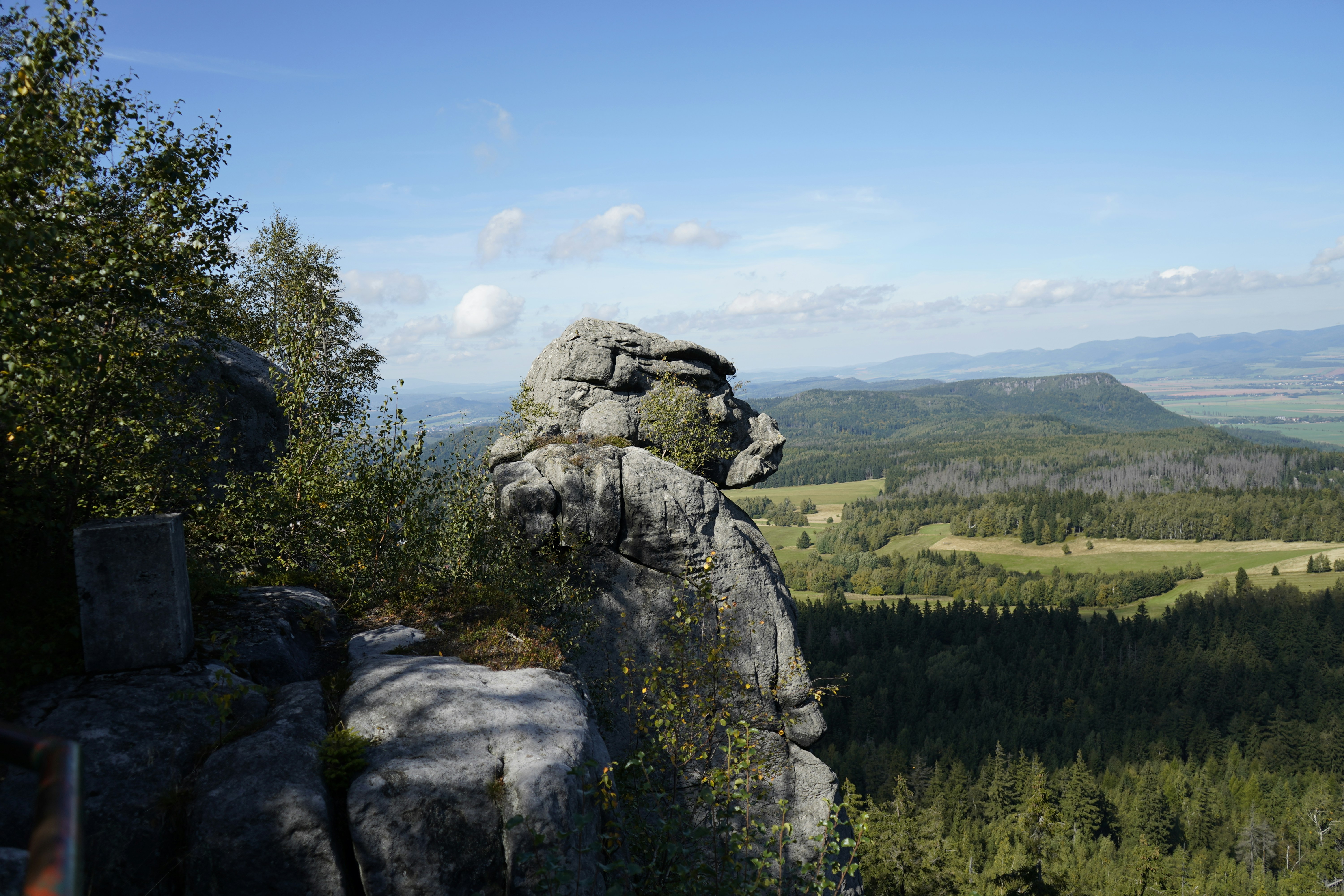Sentinel on the Edge: A Stone Figure Overlooking Rolling Valleys