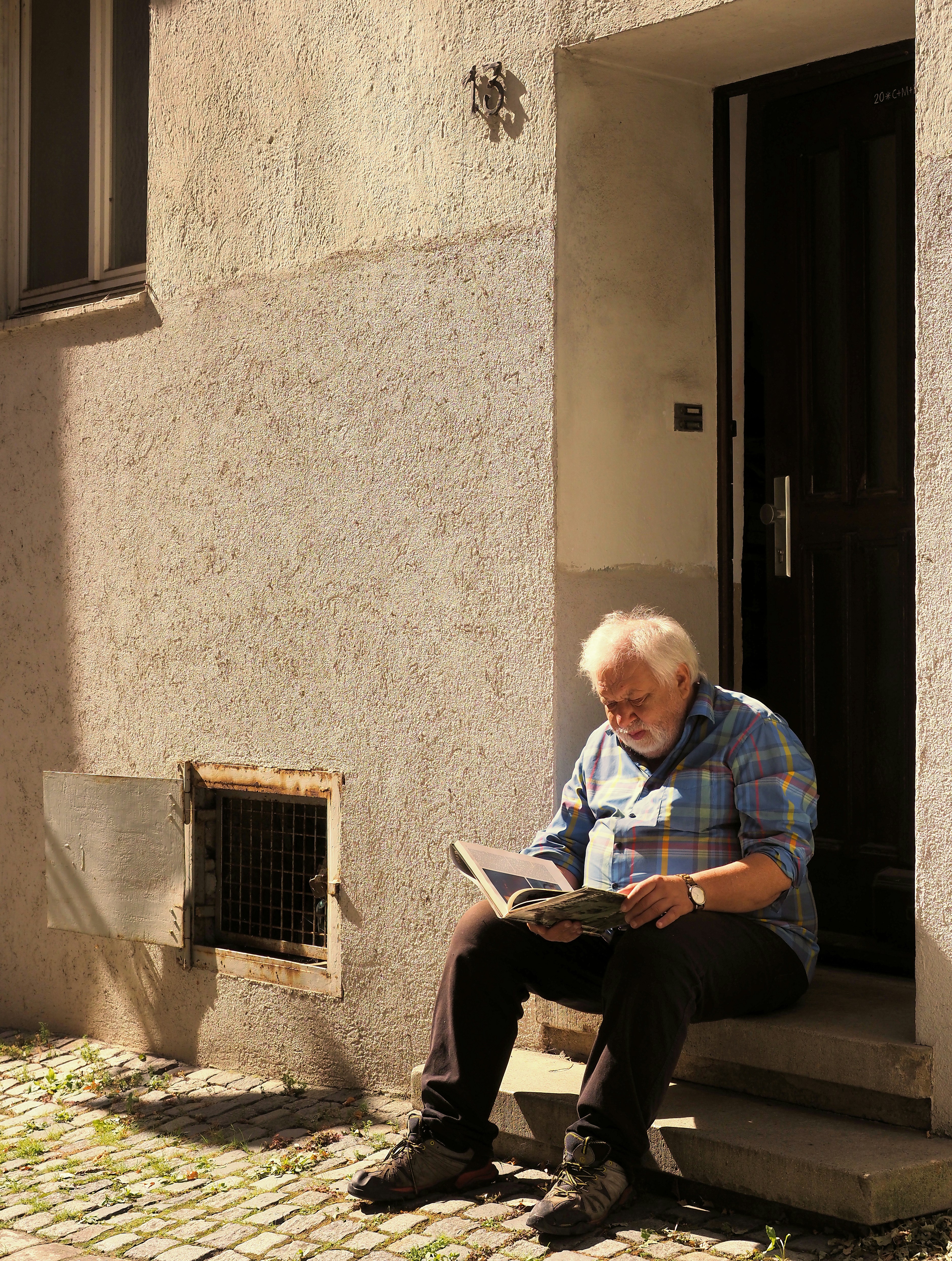 Old Reader on a Cobblestone Step