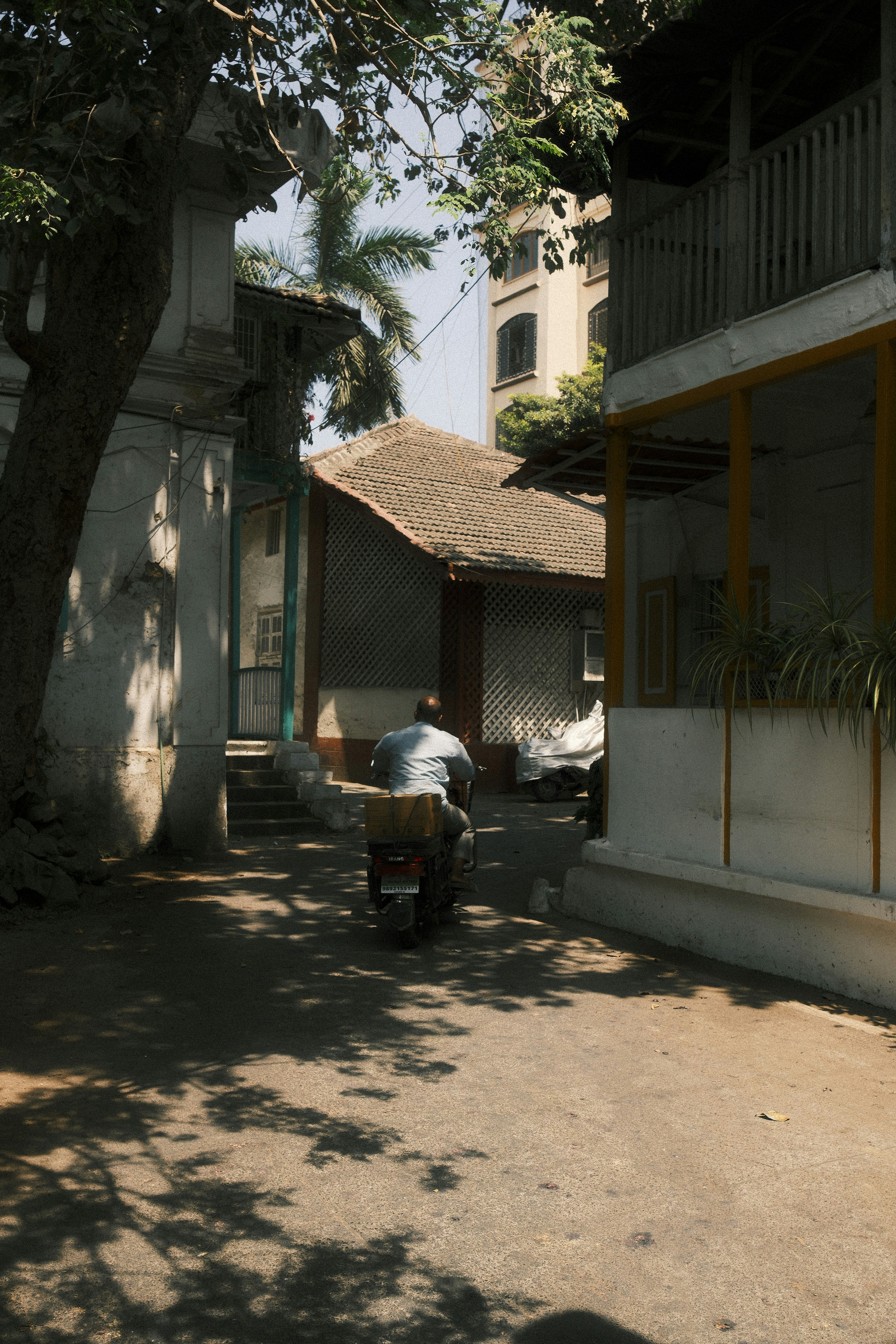 Motorbike through a sunlit alley of faded colonial charm