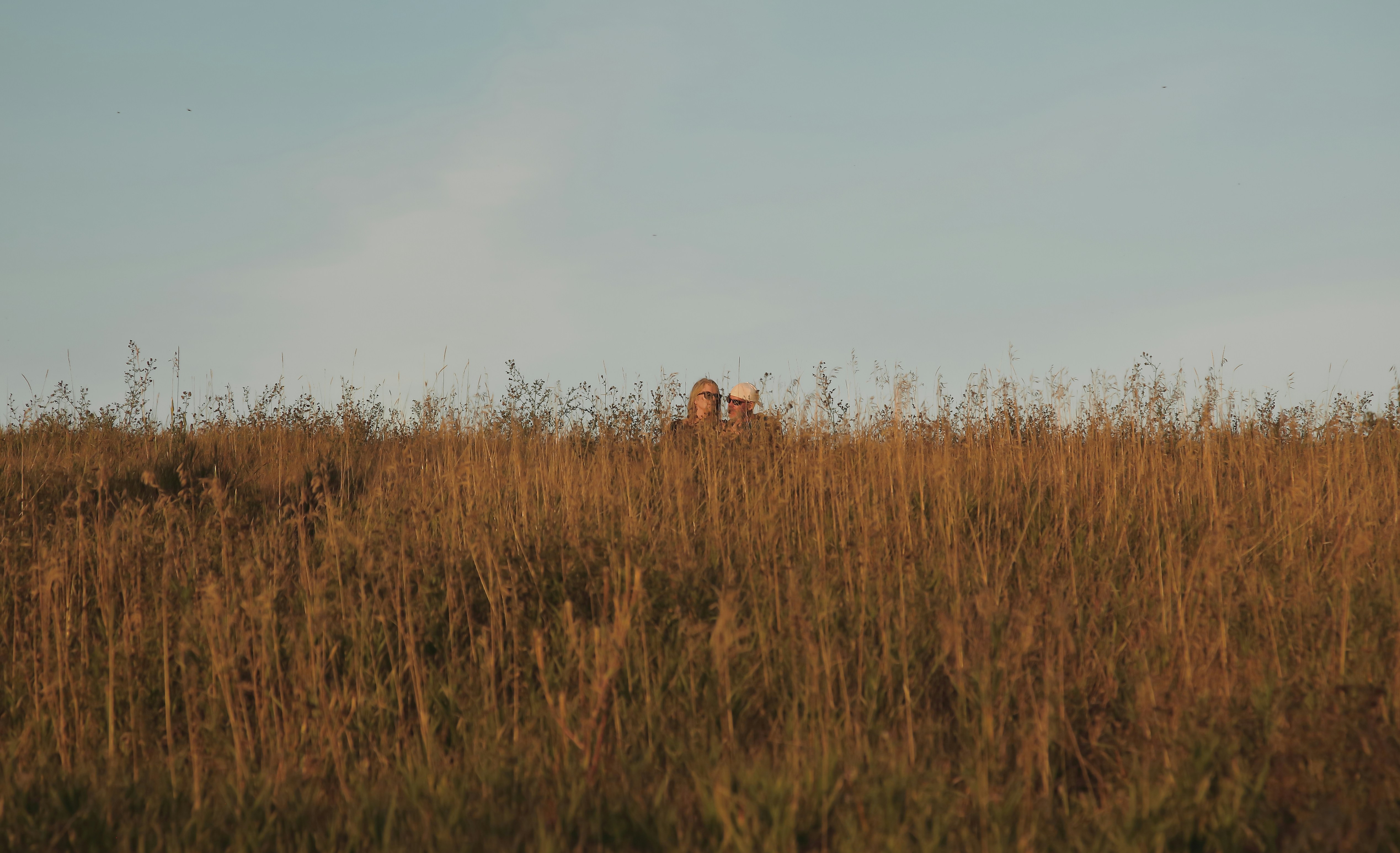 Two people peek over a hill.