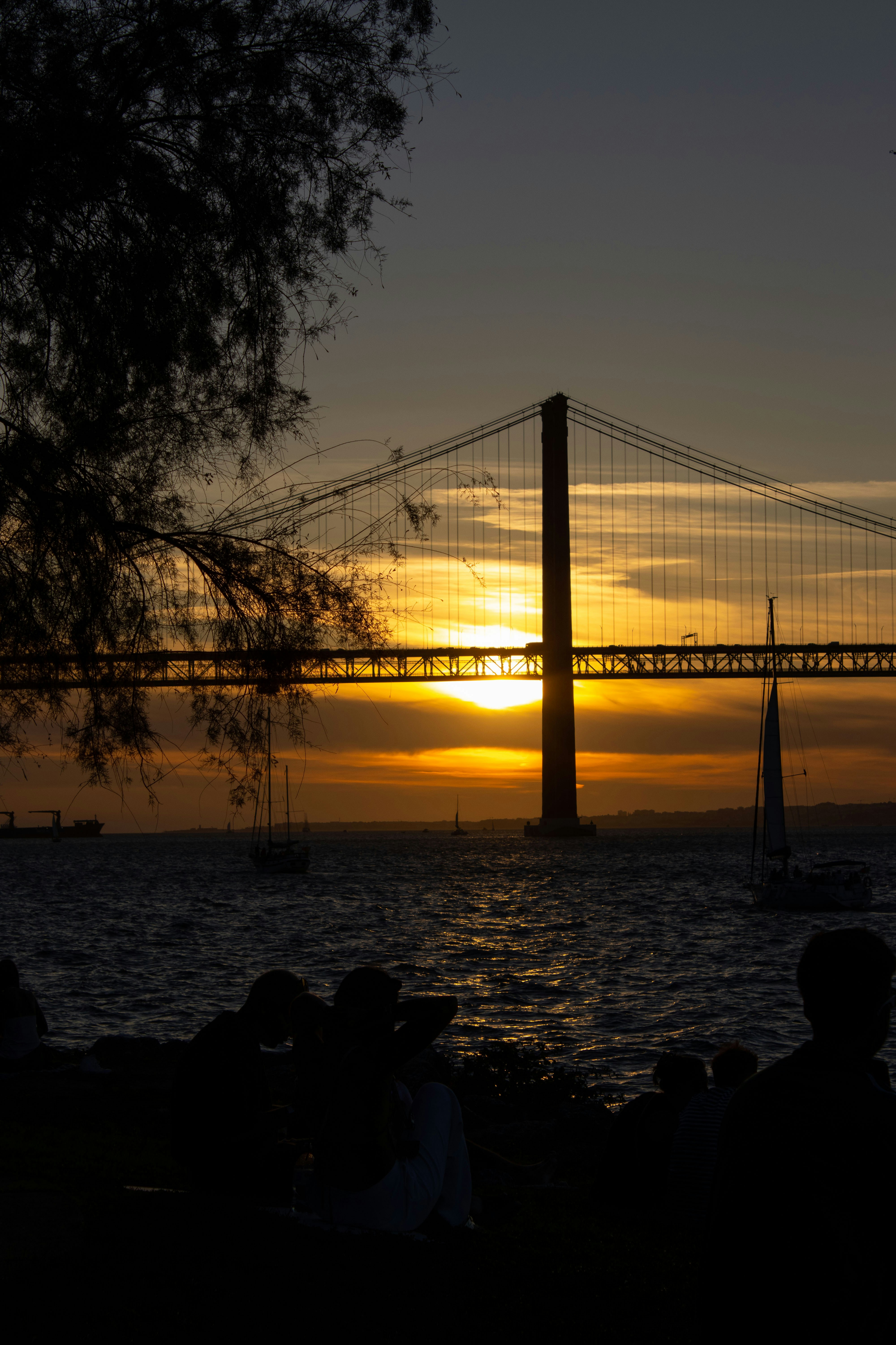 Sunset over the river with silhouetted bridge and crowd