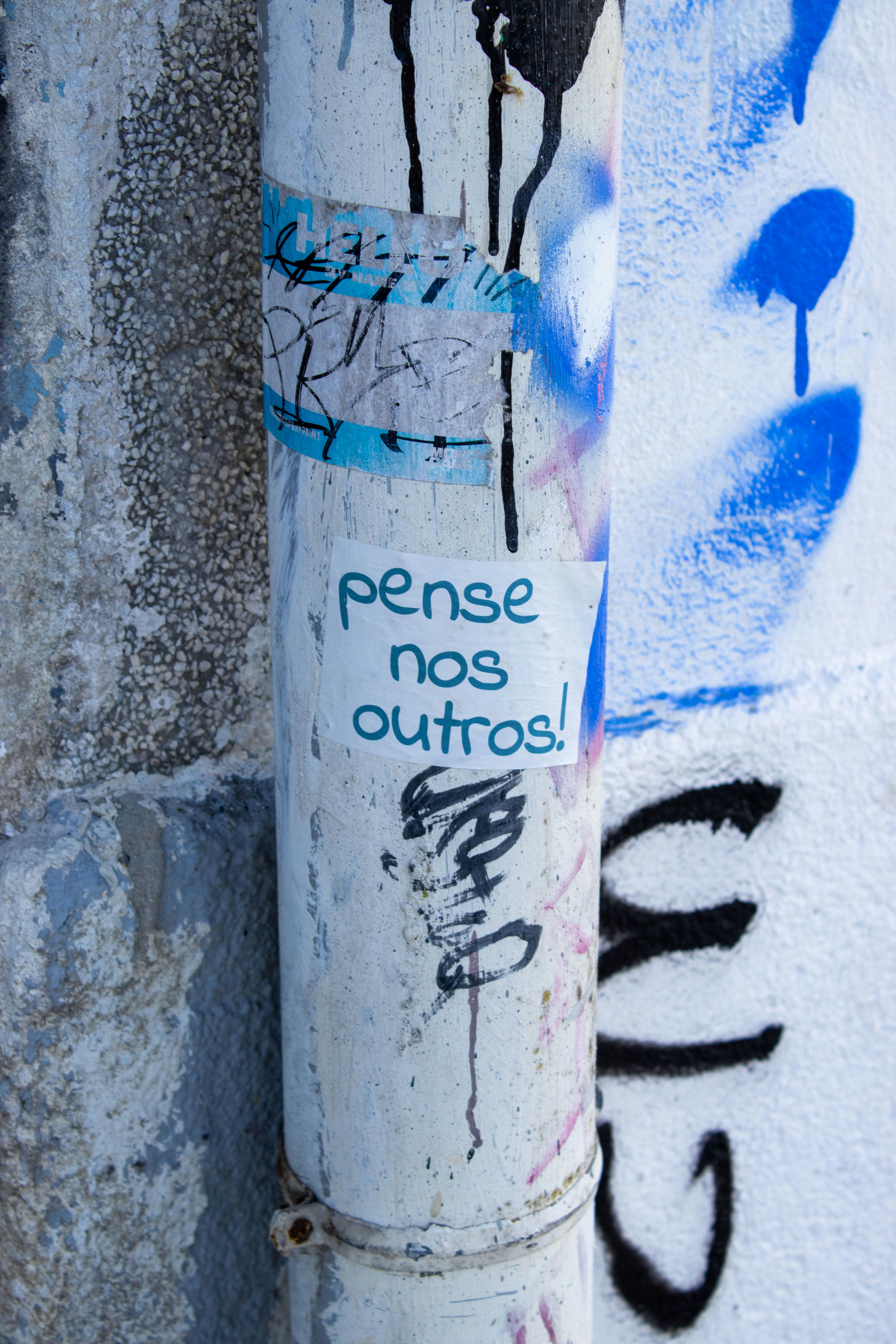 Blue sticker on graffiti-coated pipe: a message to think of others