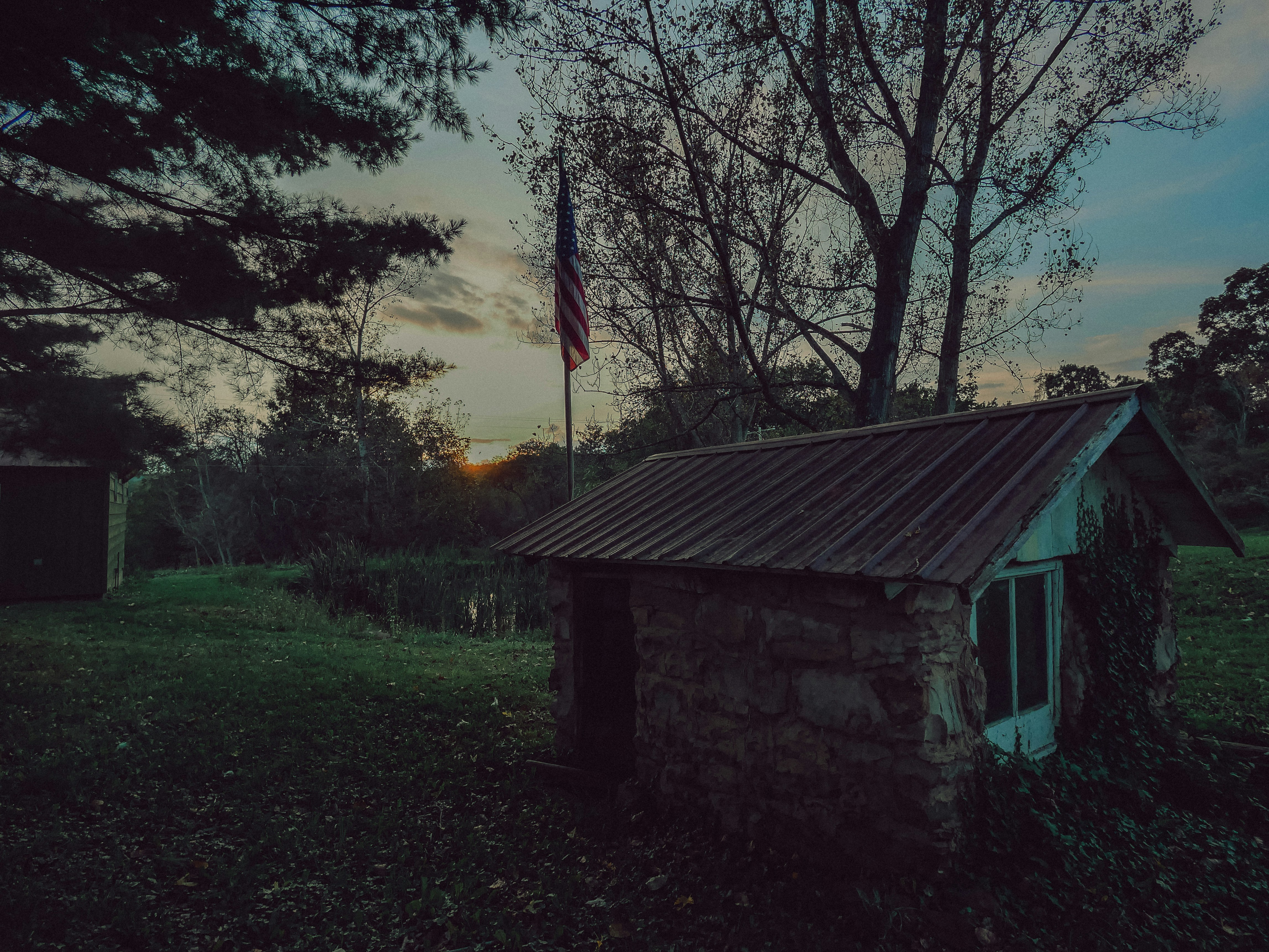 Flag at Dusk Over a Humble Stone Shelter