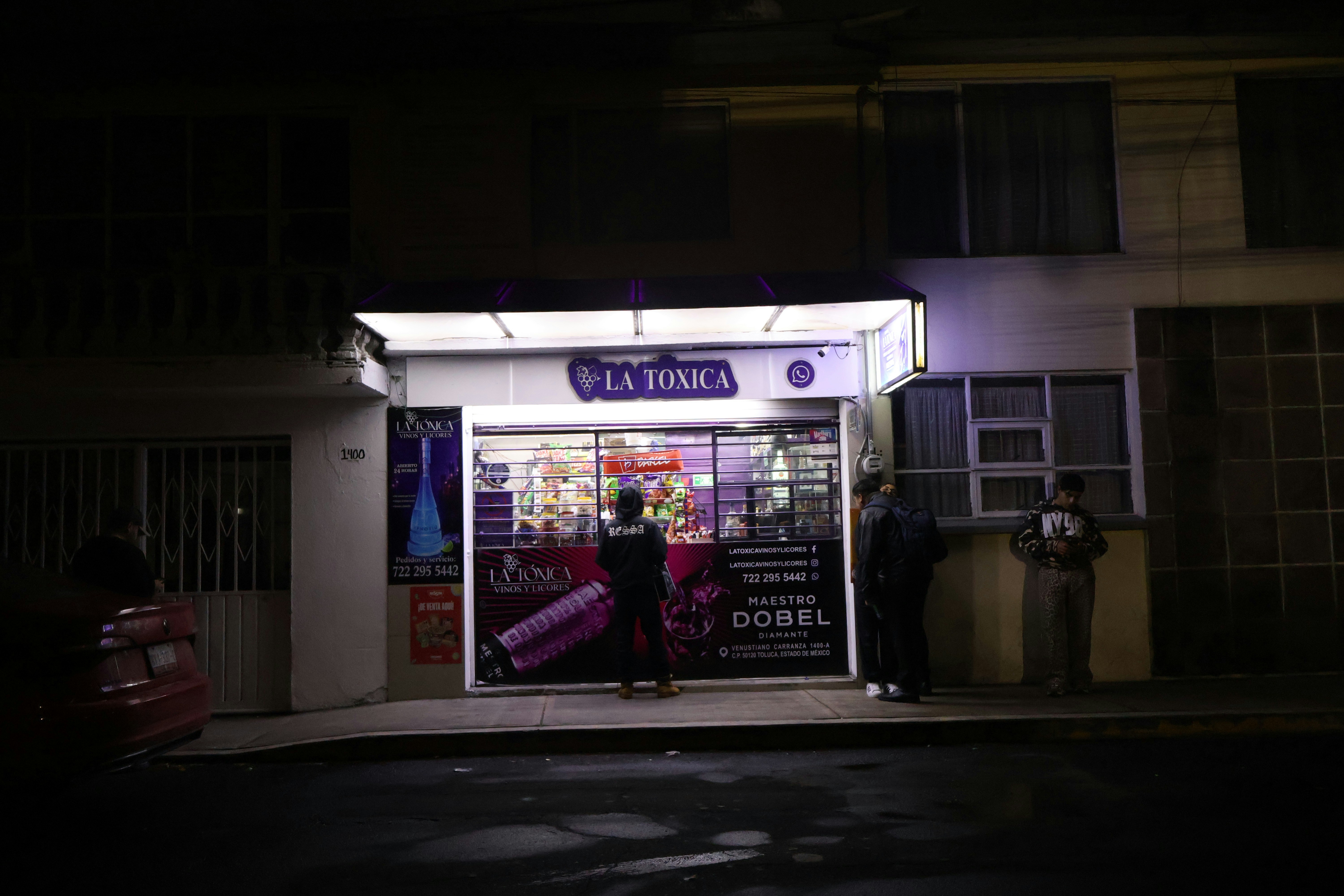 Midnight storefront: neon glow and quiet figures at La Toxica