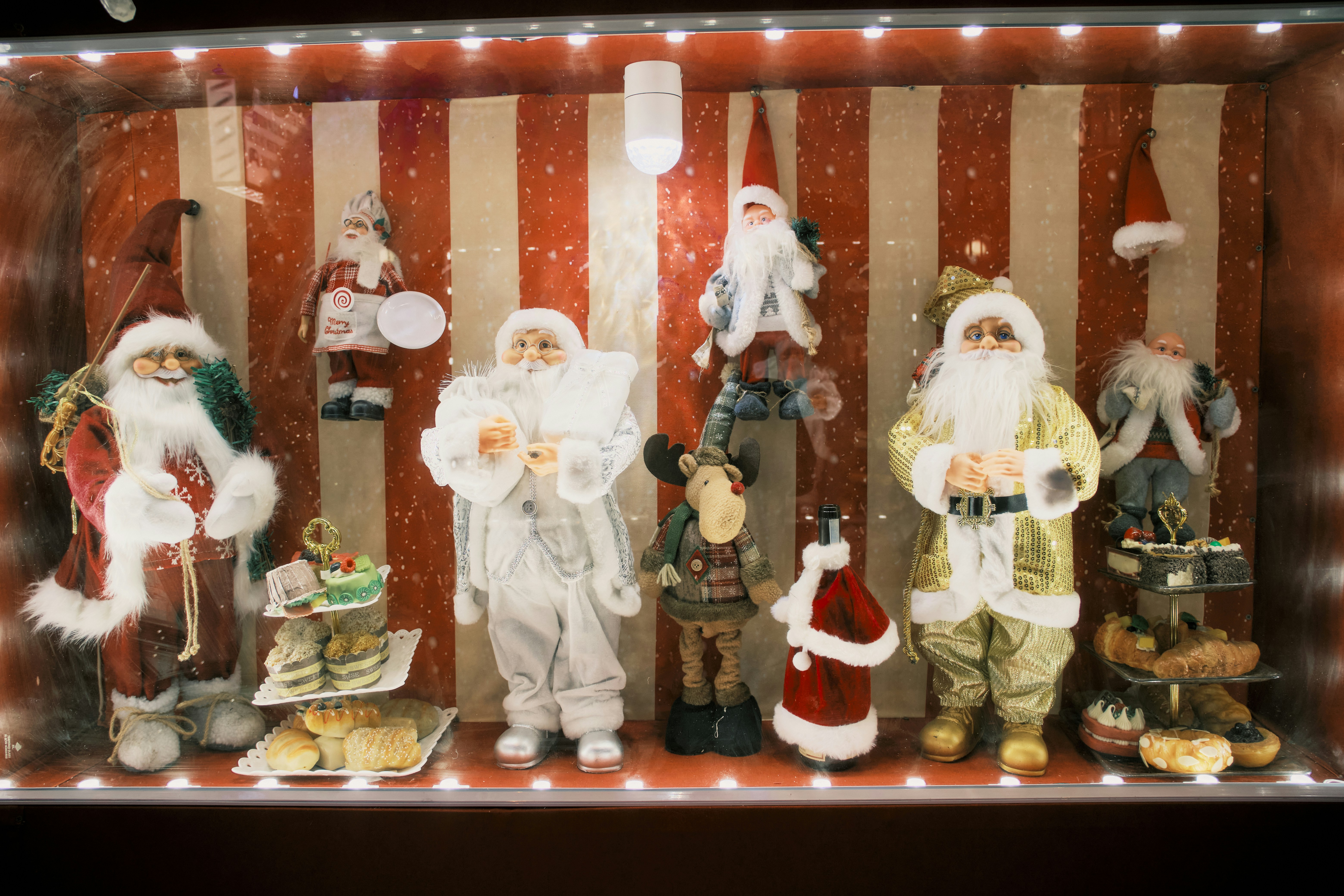Row of Festive Santa Figures in Red-Striped Display Cabinet