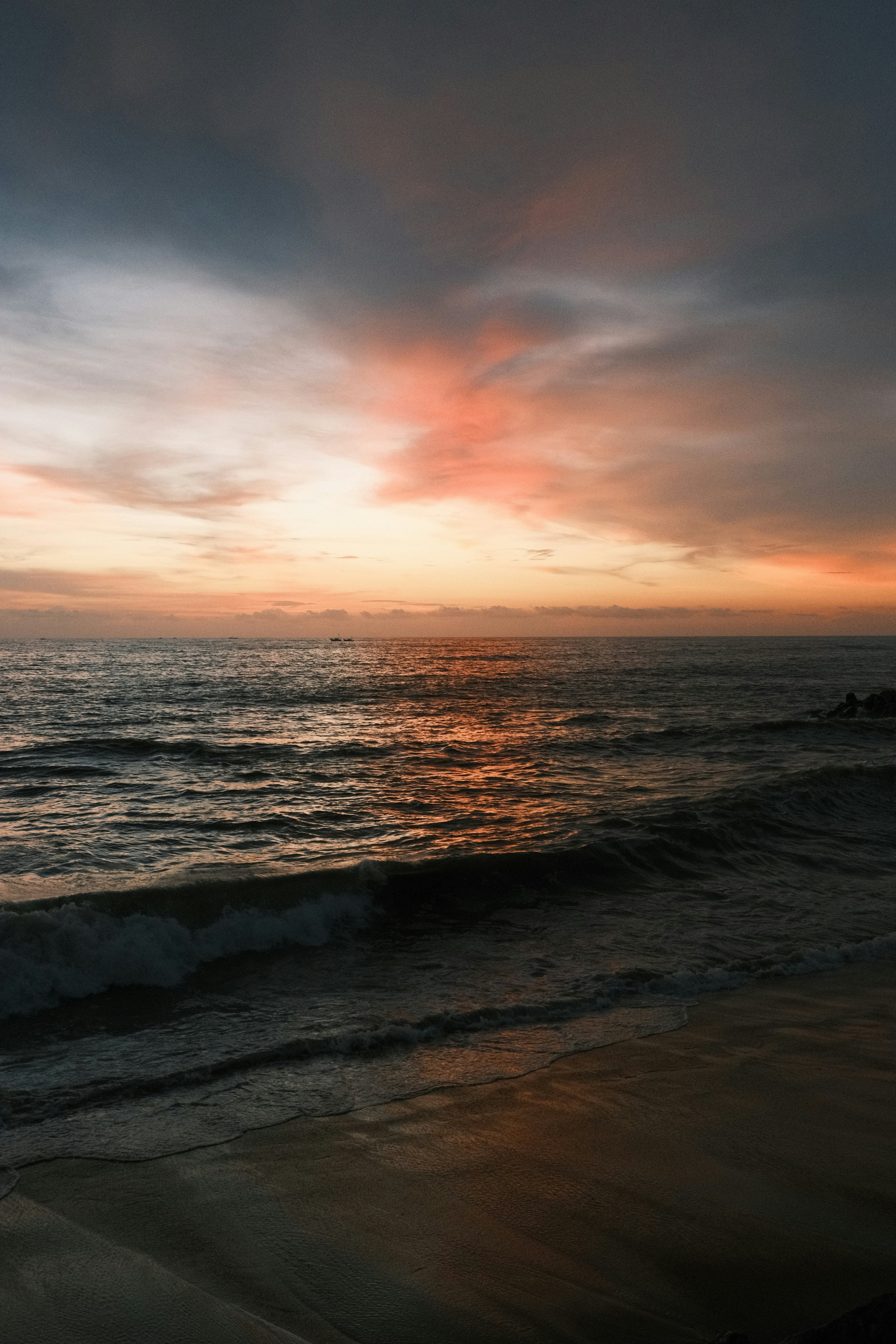 Twilight Coastal Calm: Orange Veil Over Slumbering Waves