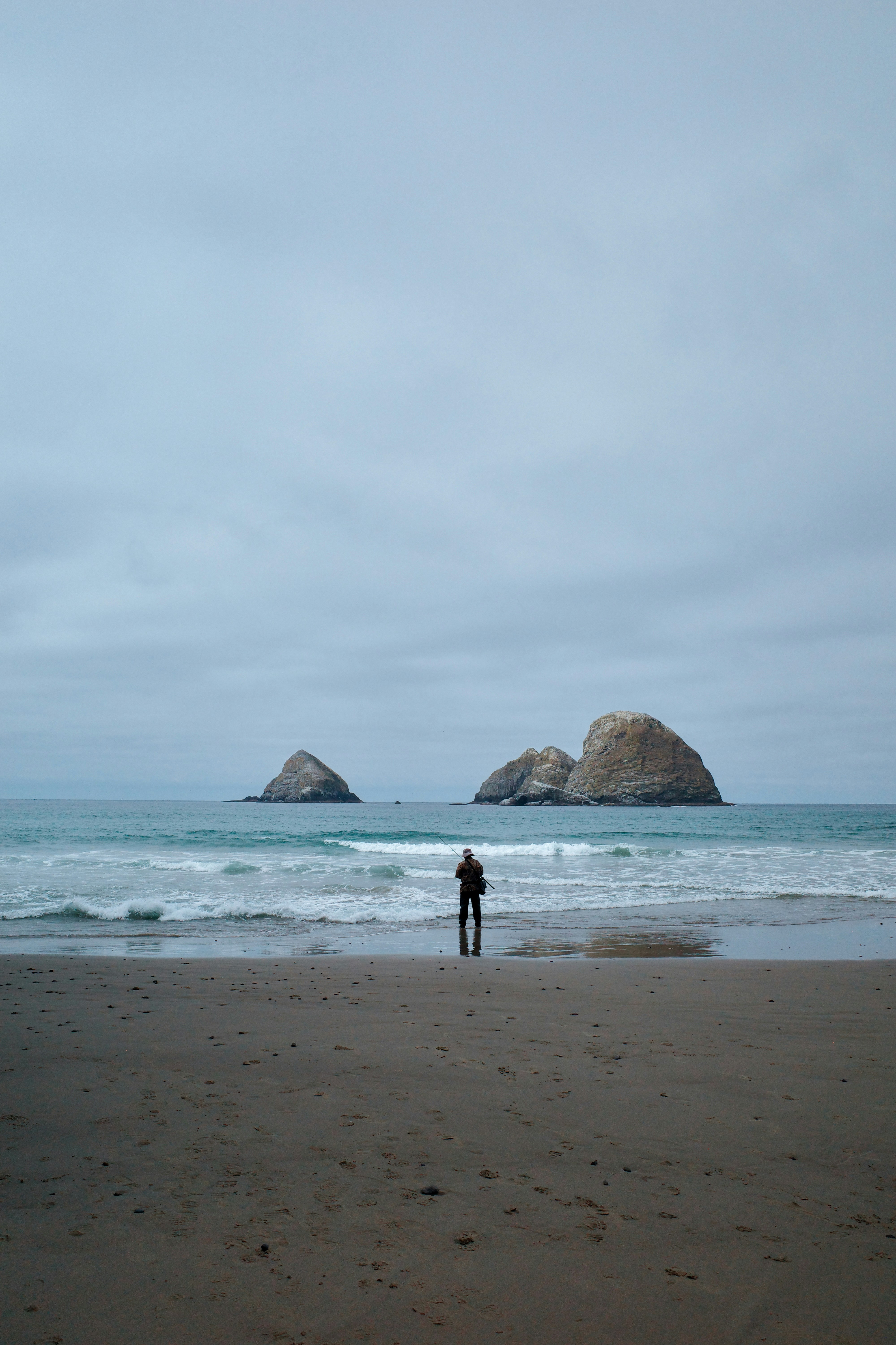  solitary surfer at the edge of breaking waves between distant rock islets