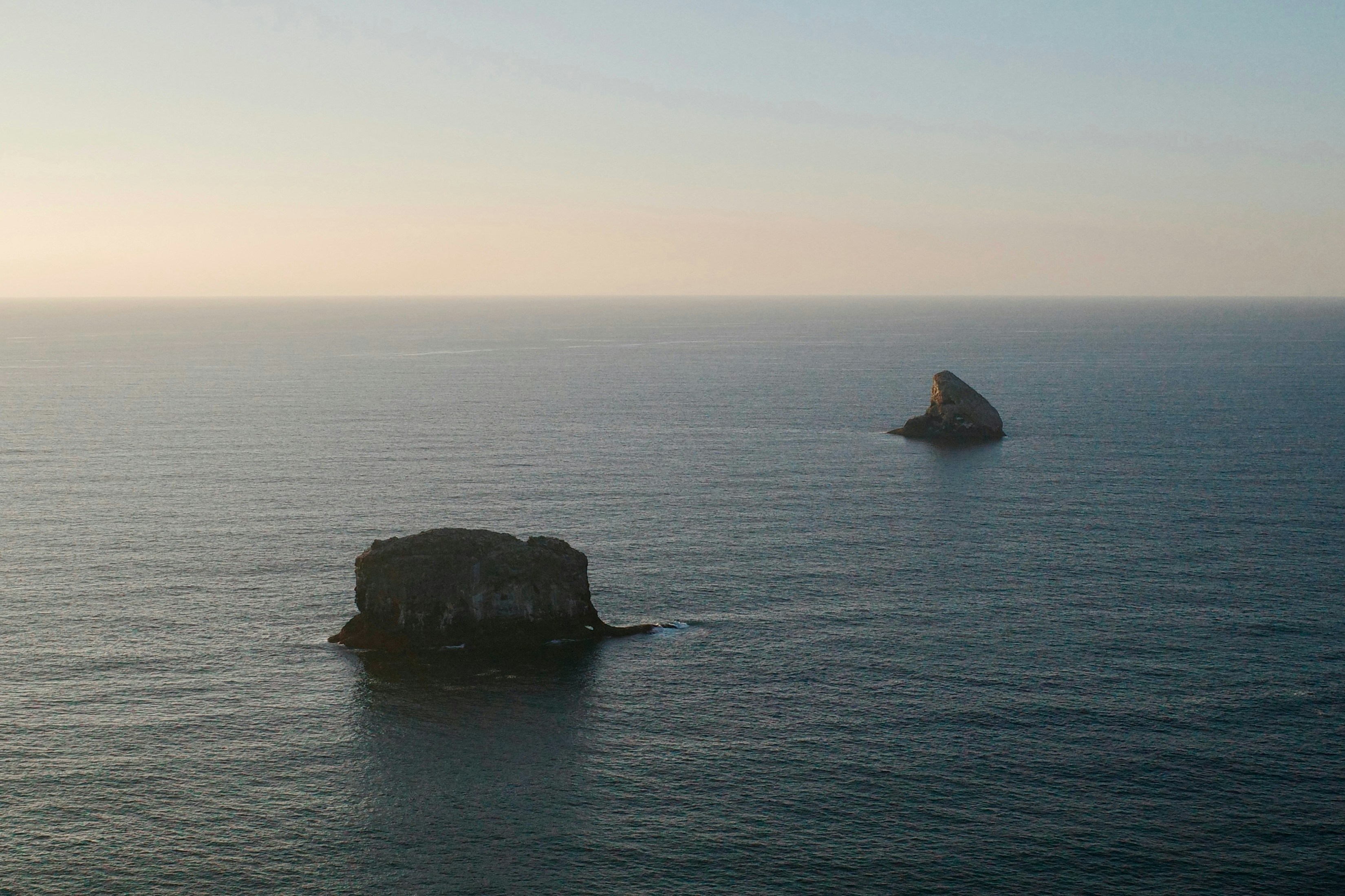 Isolated Sea Stack at Dusk: A Calm Break in the Horizon