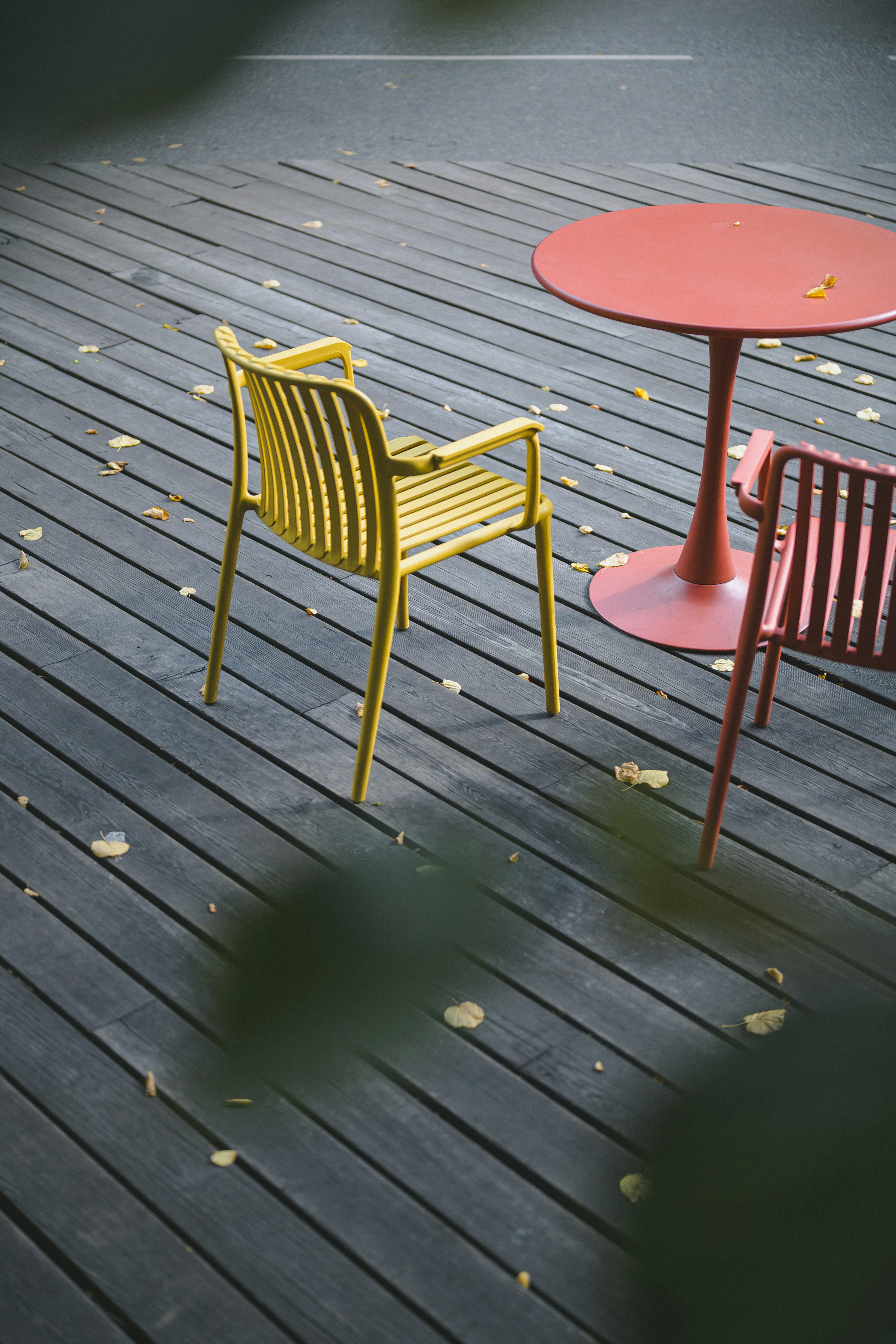 Yellow Chair and Red Table on a Wooden Deck