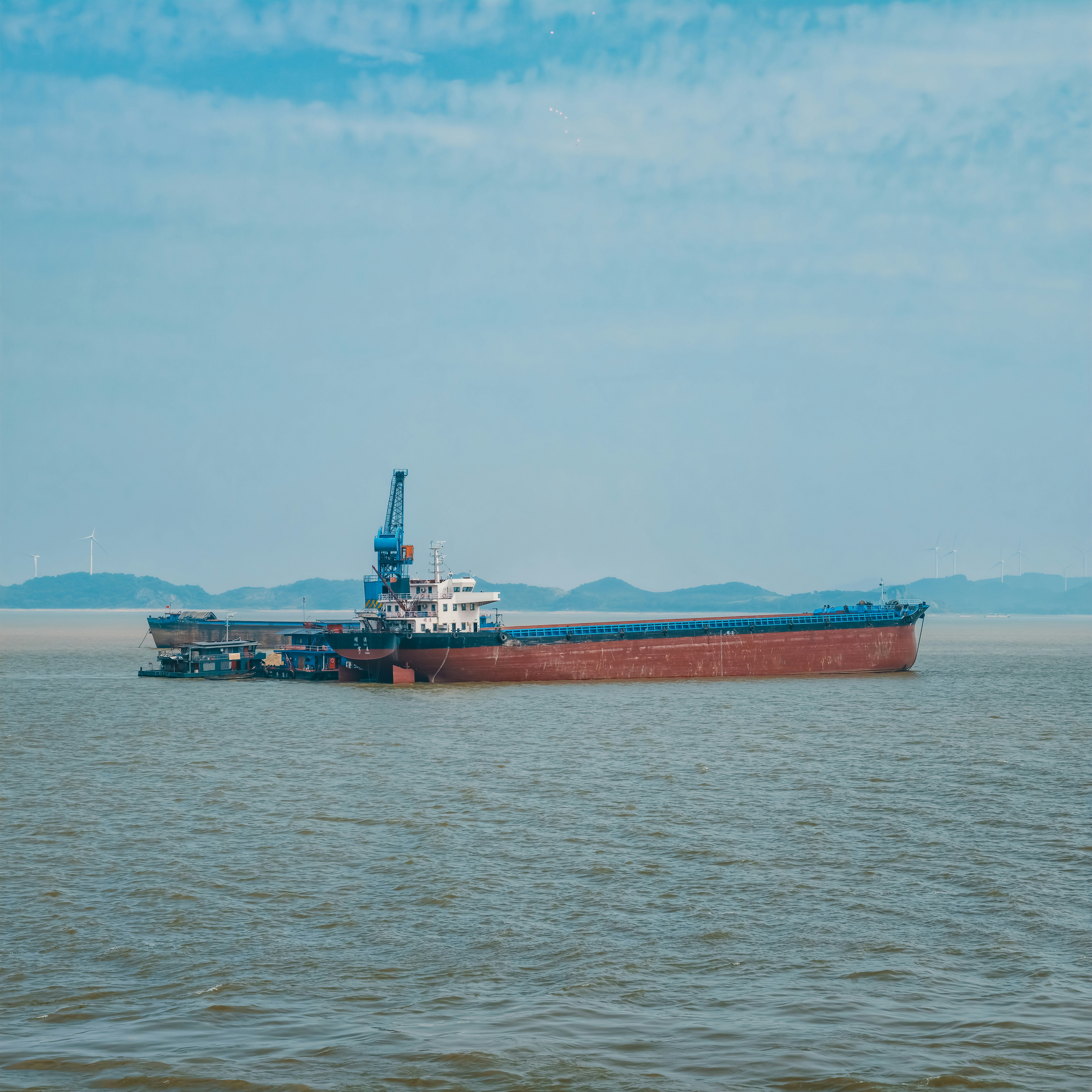 Red-hulled cargo barge resting on tidal brown-green waters