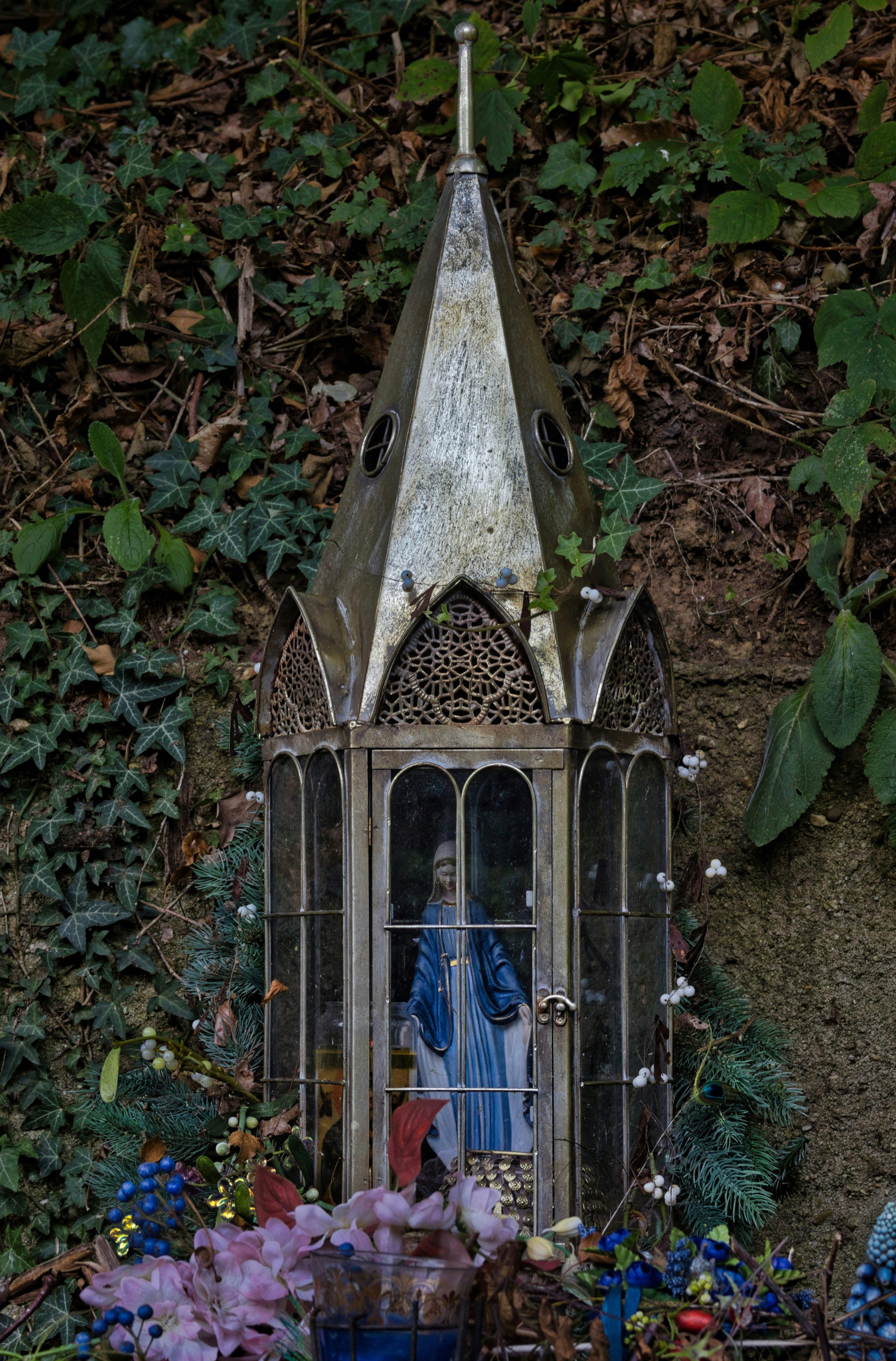Medieval Glasshouse Shrine: A Quiet Figurine Among Ivy and Flowers