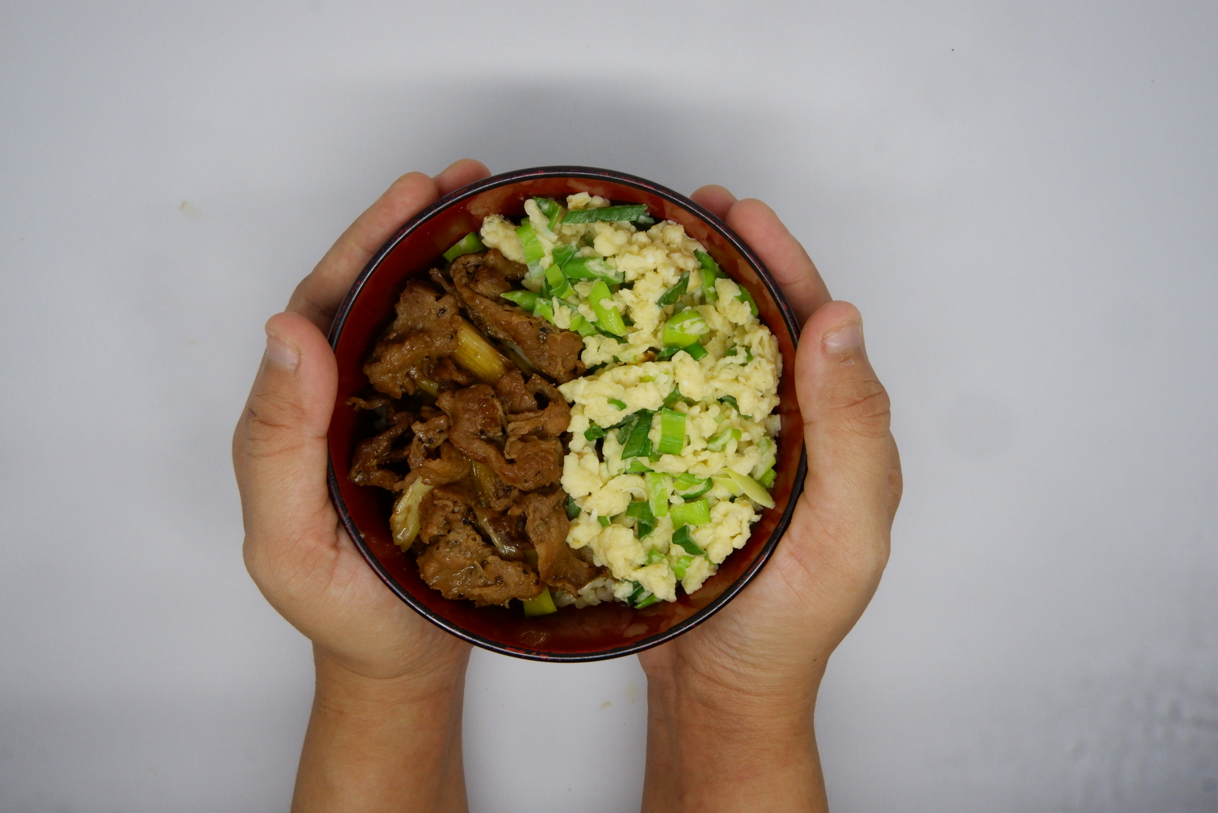 Hands Cradle a Bowl of Sizzling Beef and Rice