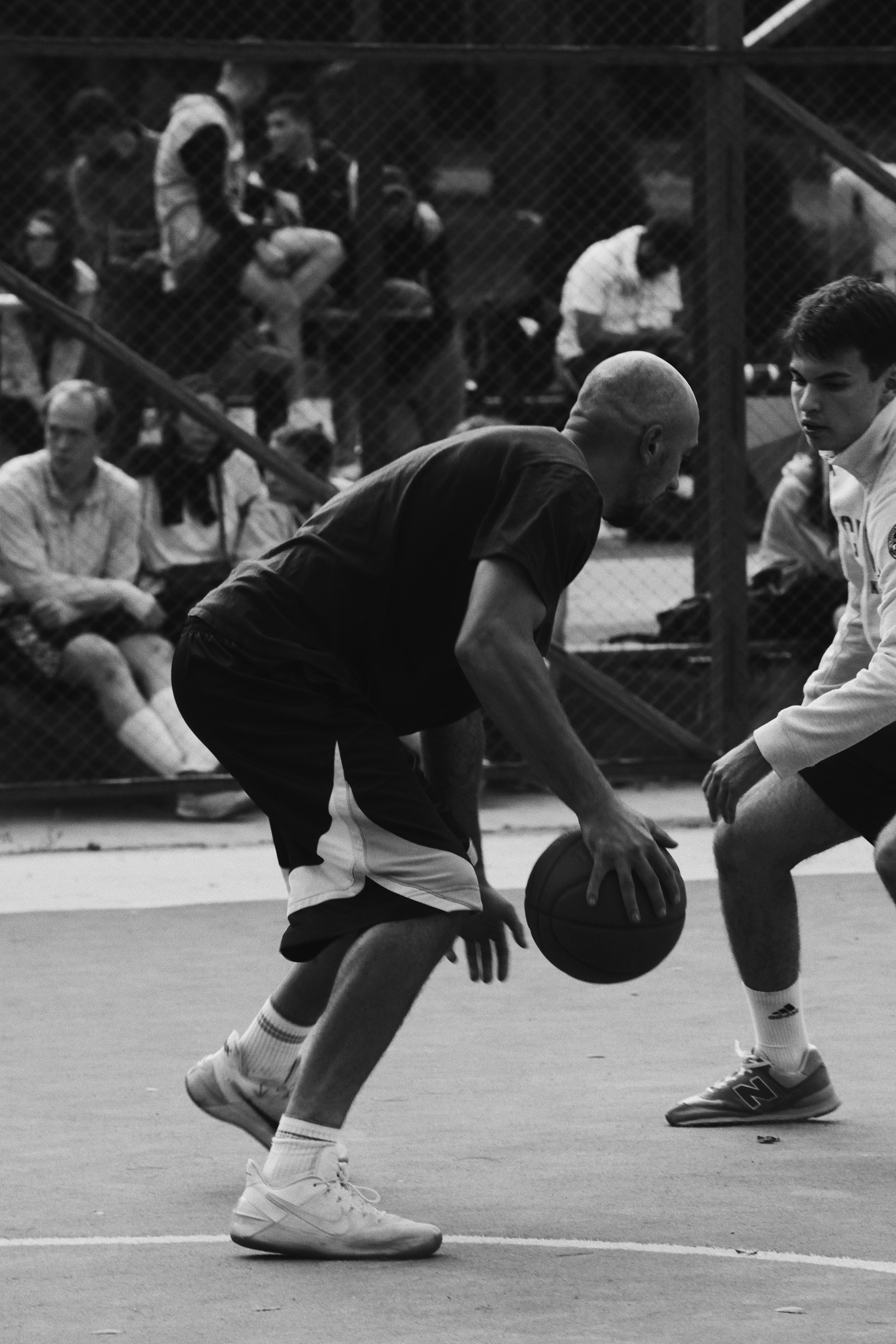 Drill in the Ring: A Bald Basketball Player Guiding the Ball Past a Challenger