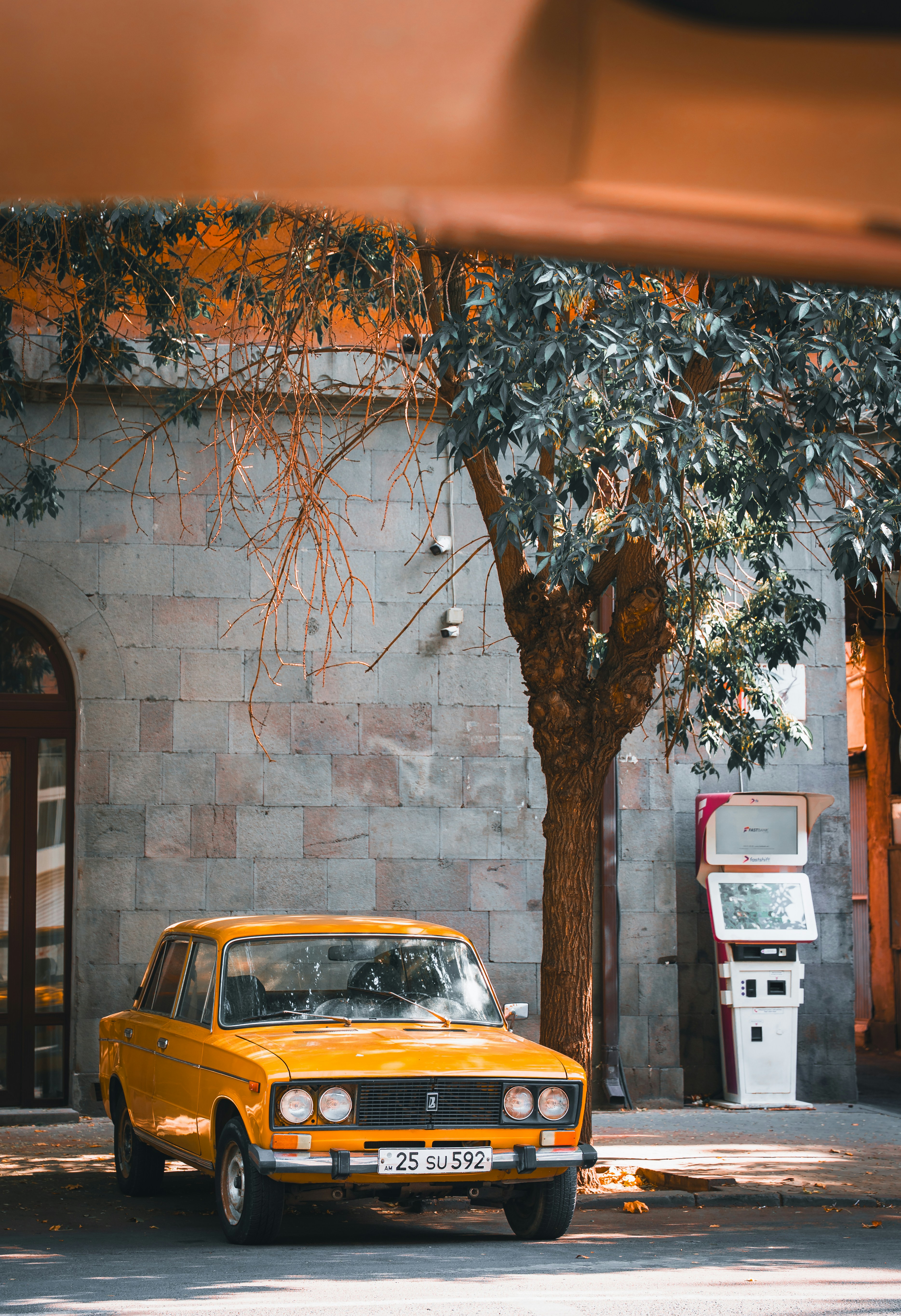 Yellow Classic: A Retro Car Under Shade on a Quiet Street