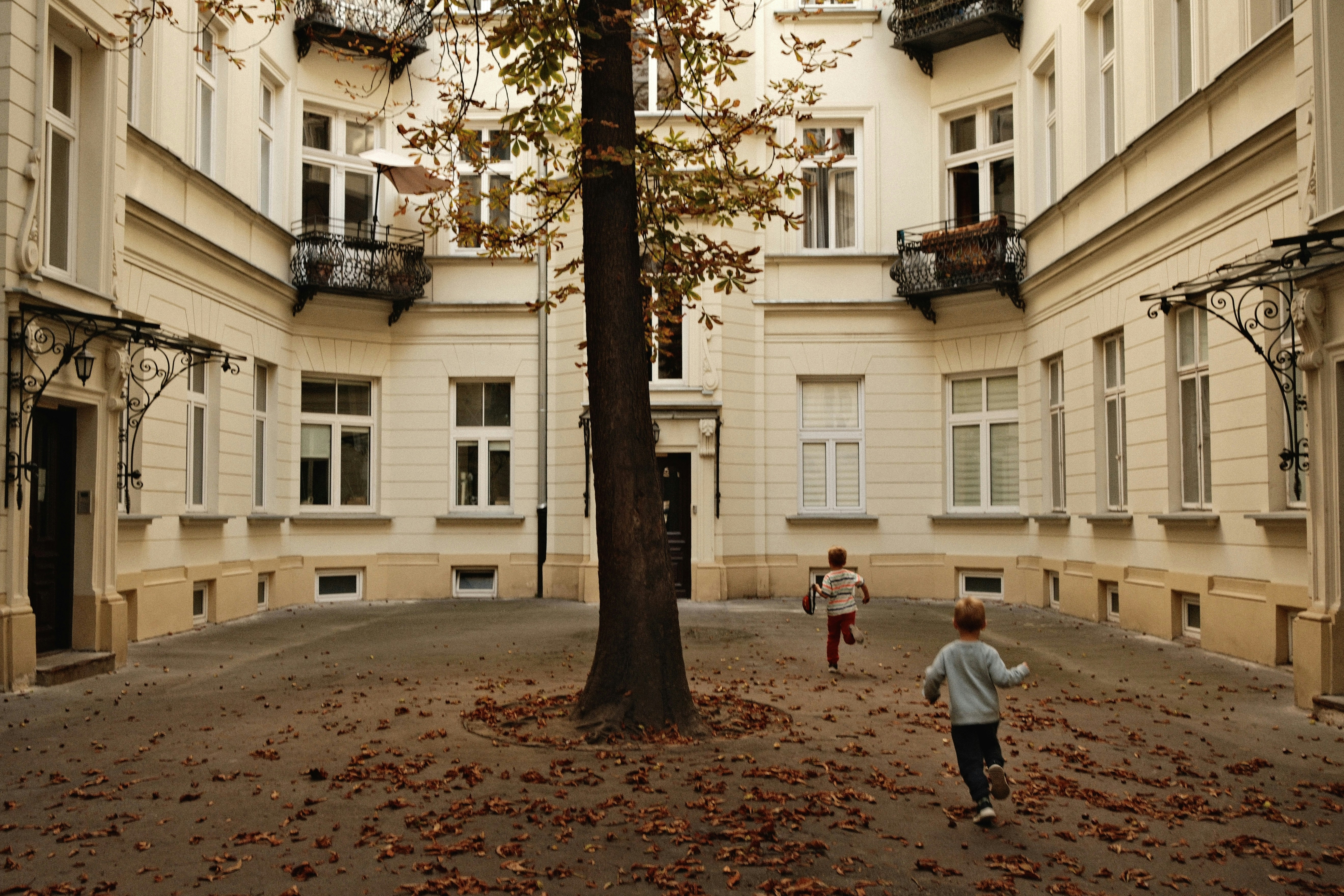 Children at the Central Tree: A Quiet Moment in a Pale Courtyard