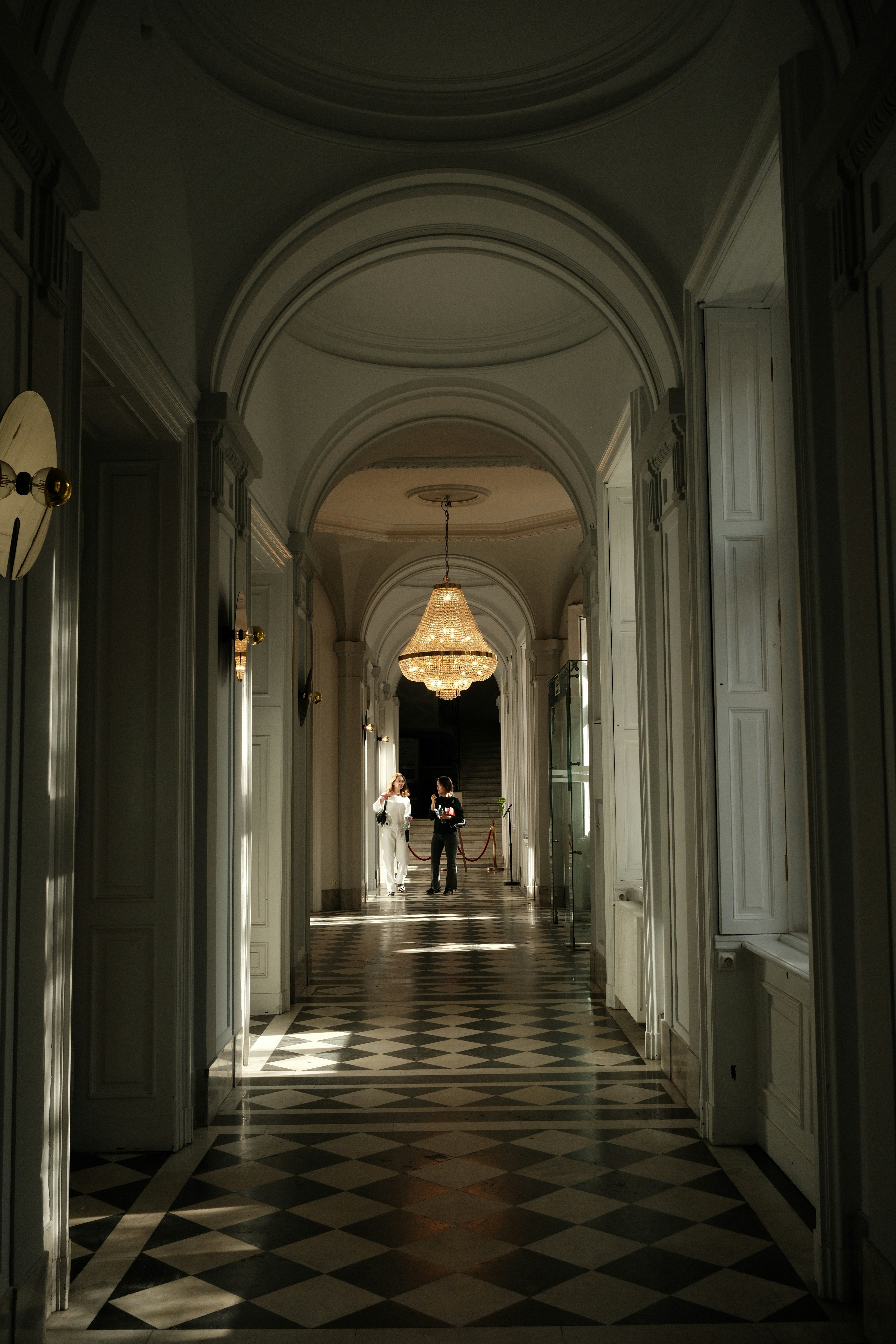 Chateau Corridor: A chandelier-lit crossing framed by arches