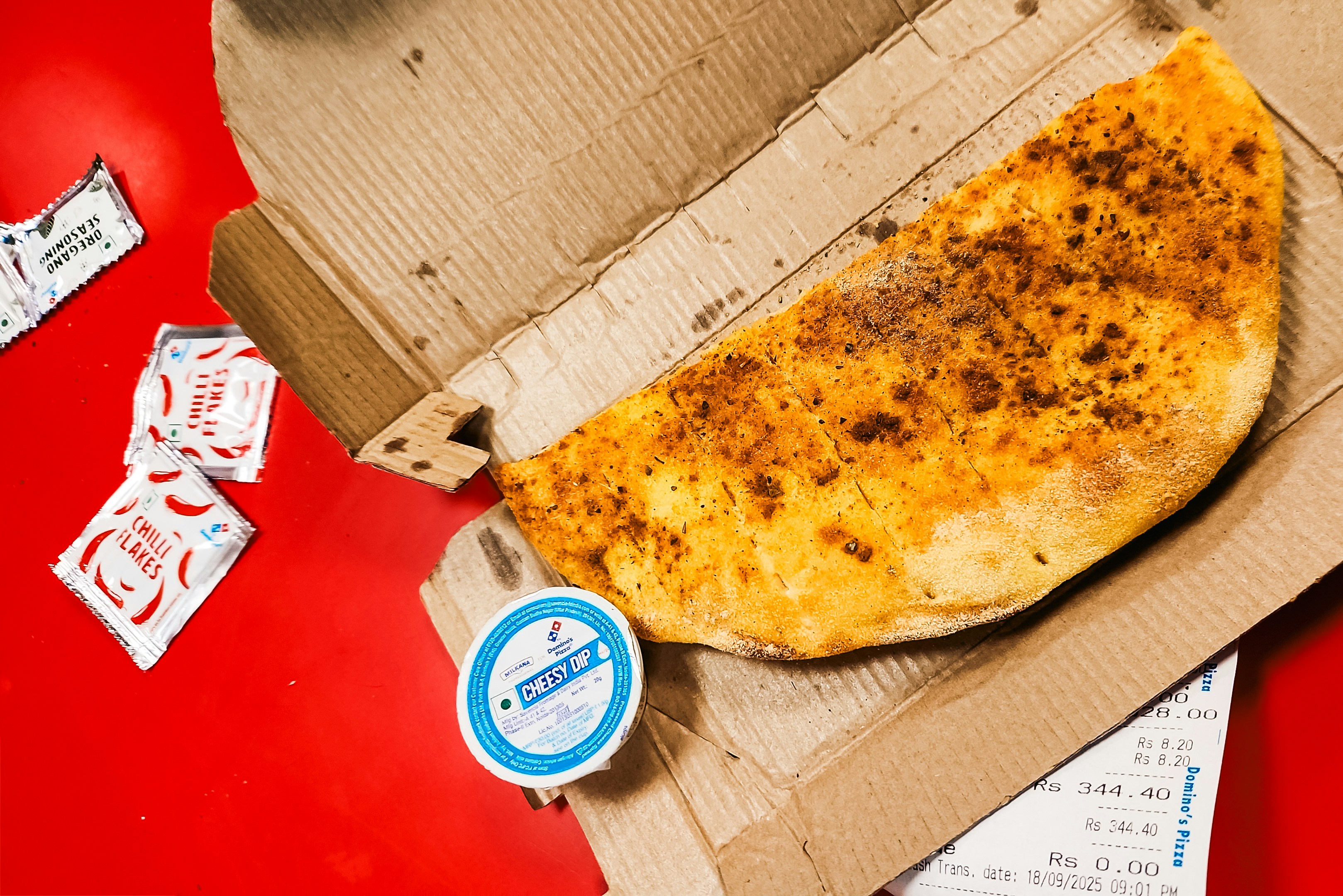 Charred Edge Pizza in Cardboard Wake on Red Counter