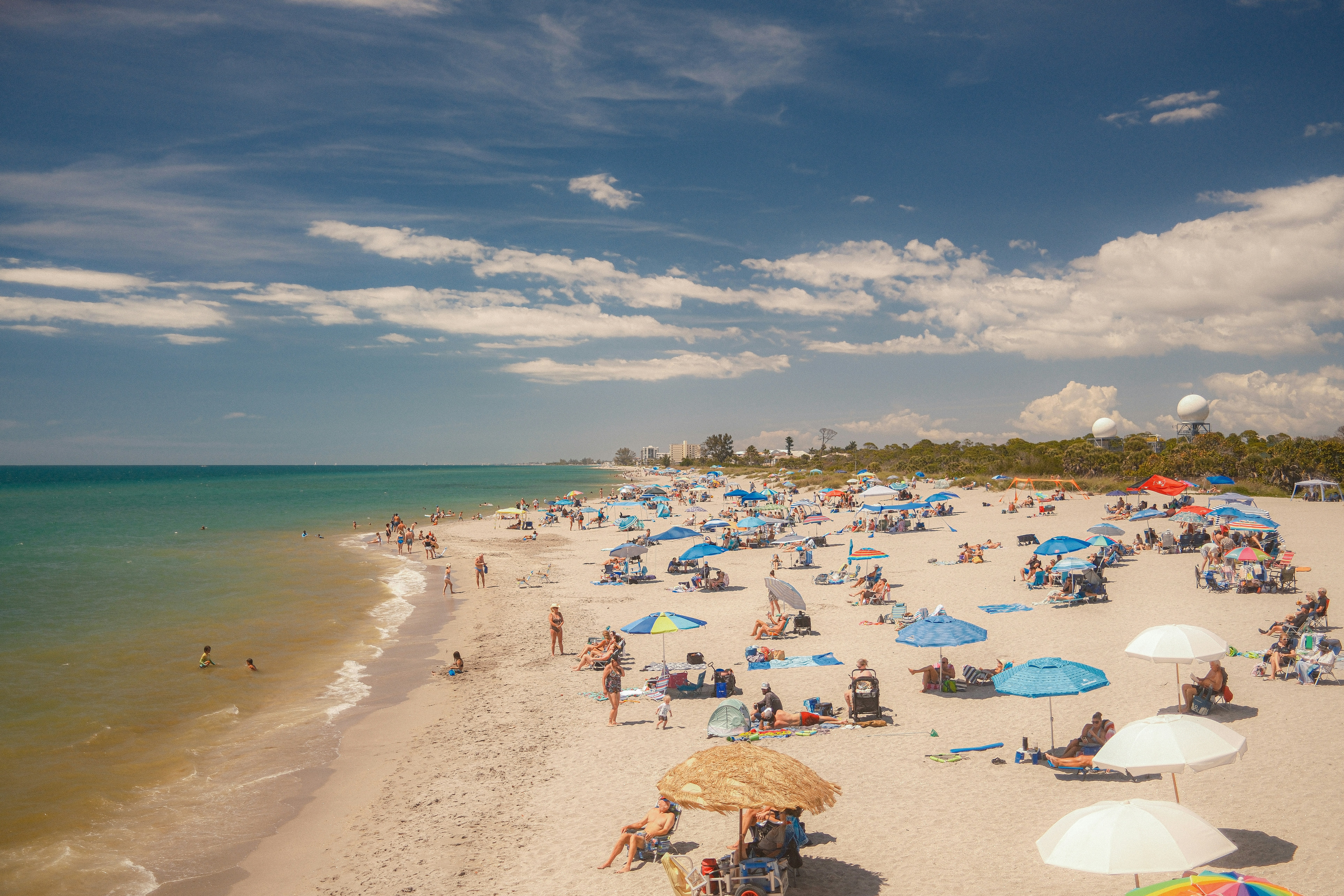 Sunlit Strand: A Bustling Coastal Day Under Cerulean Skies