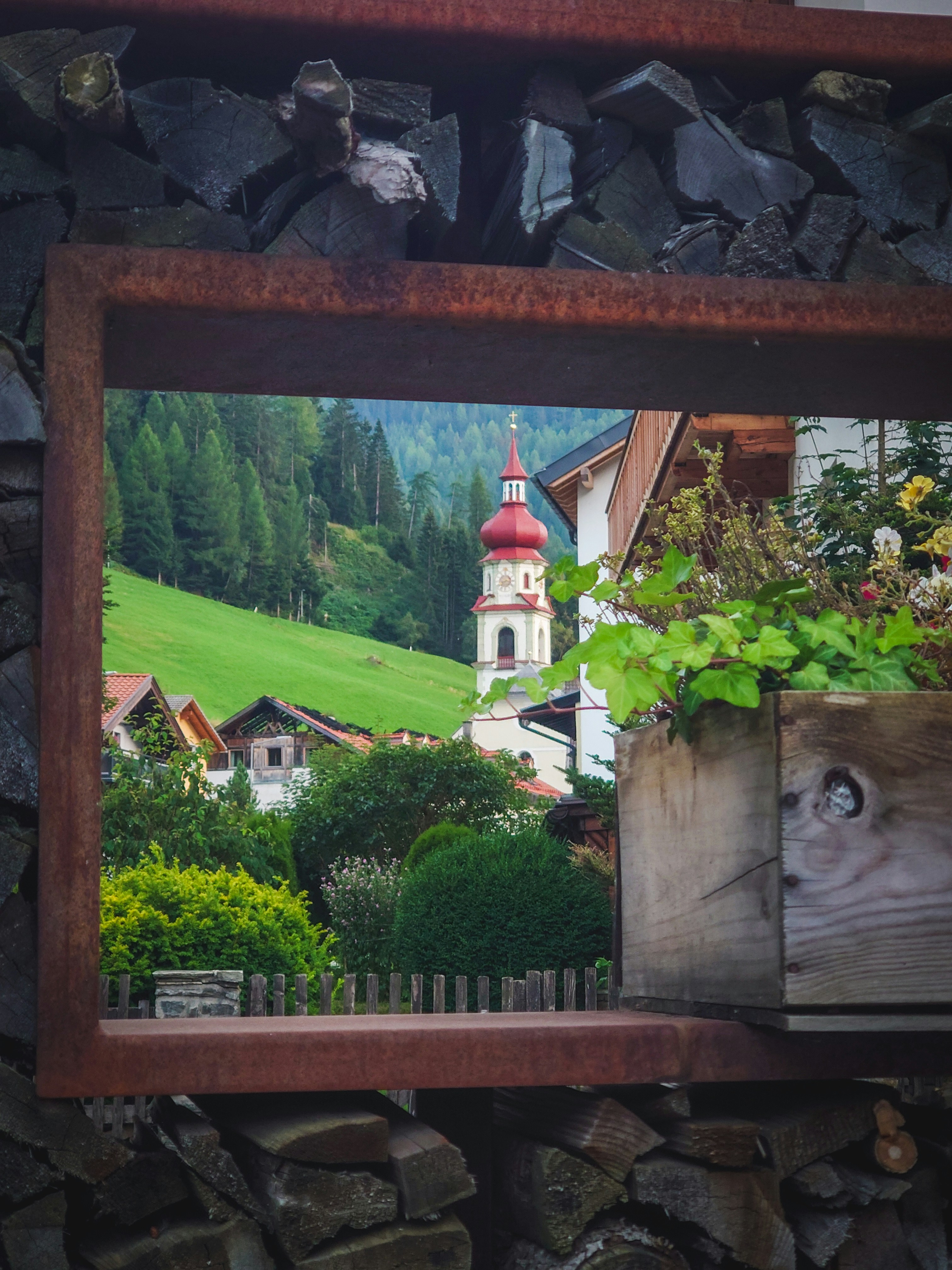 Rust-colored Frame as Portal: A Alpine Village Peeking Through Weathered Wood