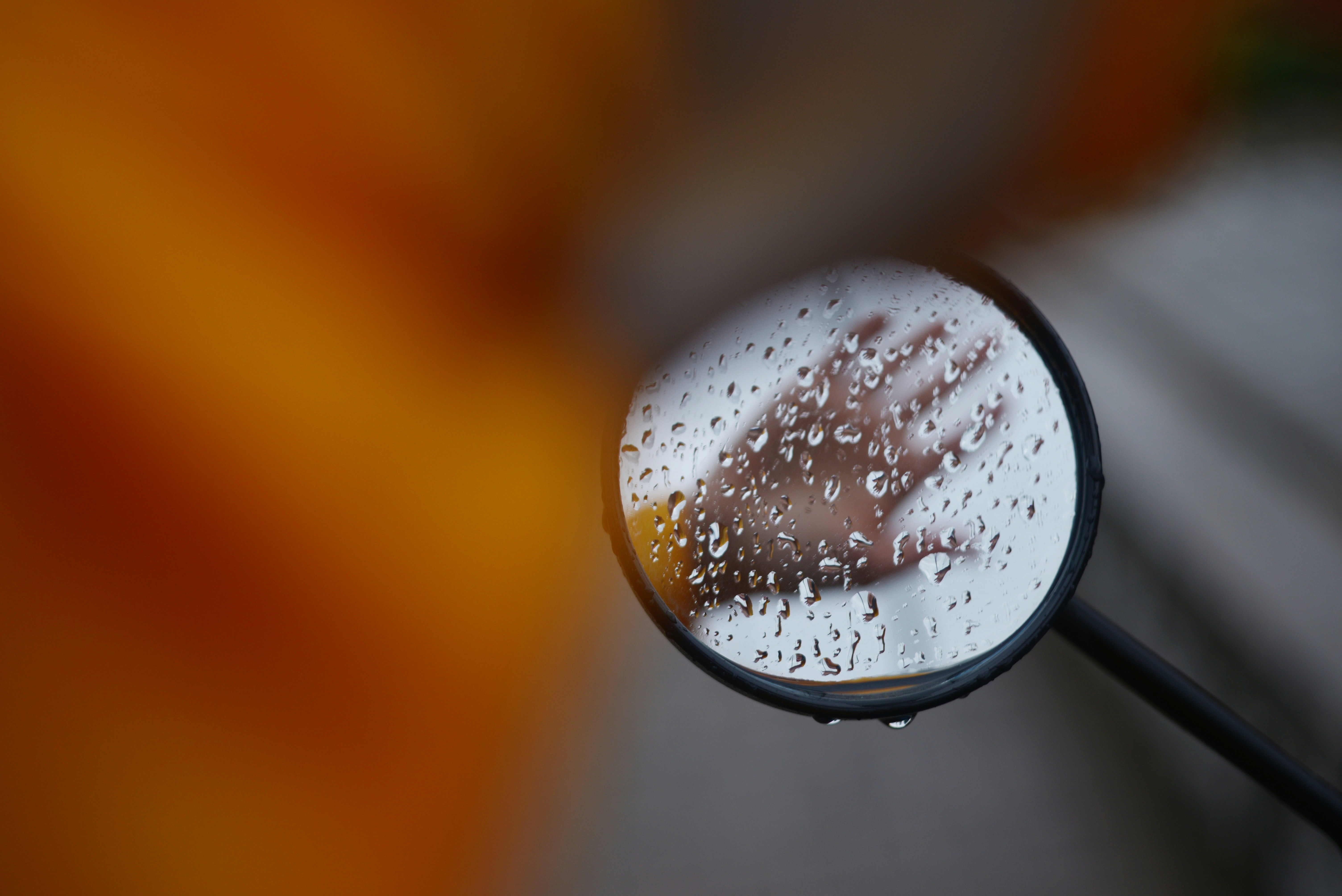 Raindrop Mirror: A Glimpse of Hand and Street Through a Water-Cleared Lens