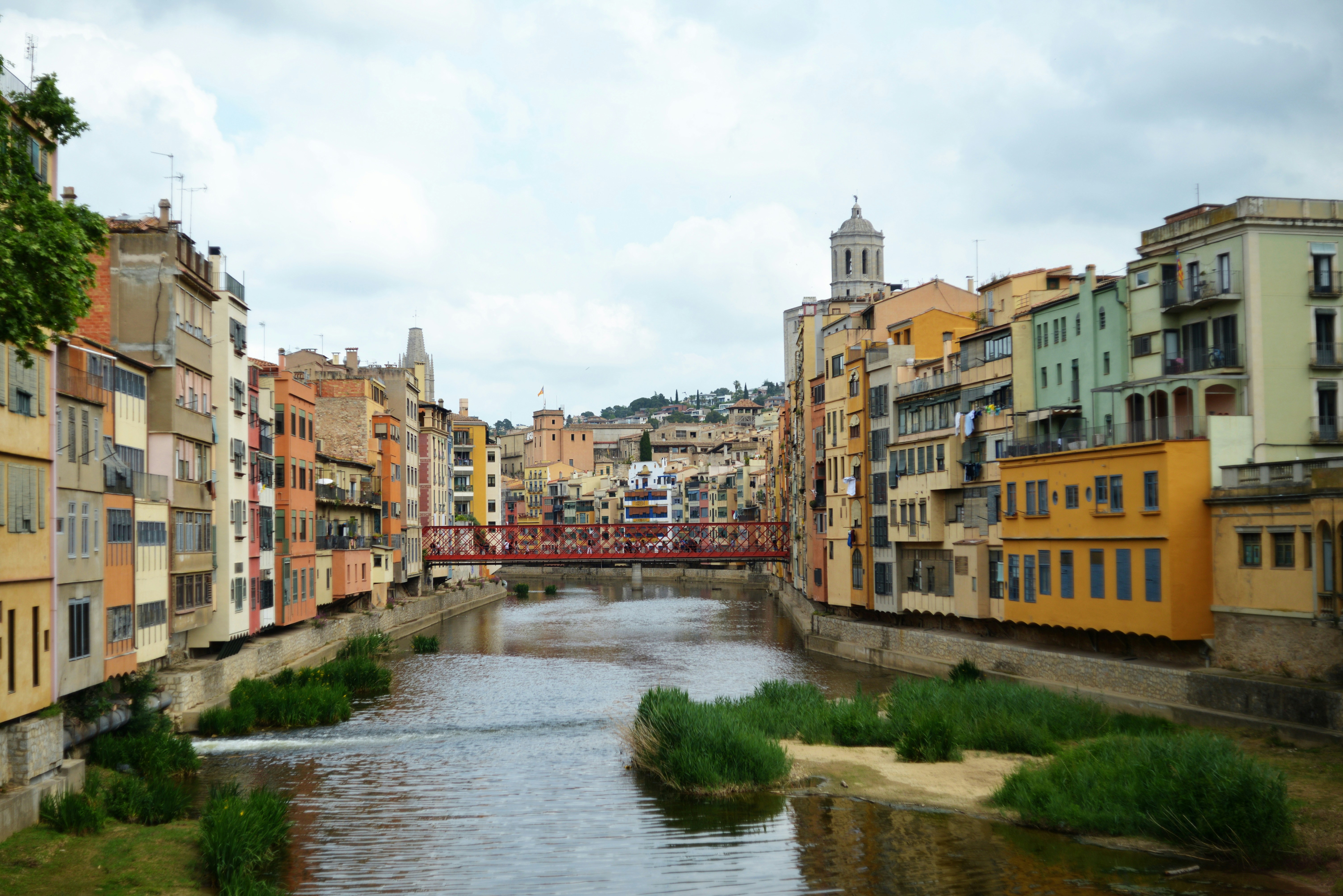 Colorful riverside village framed by a red footbridge