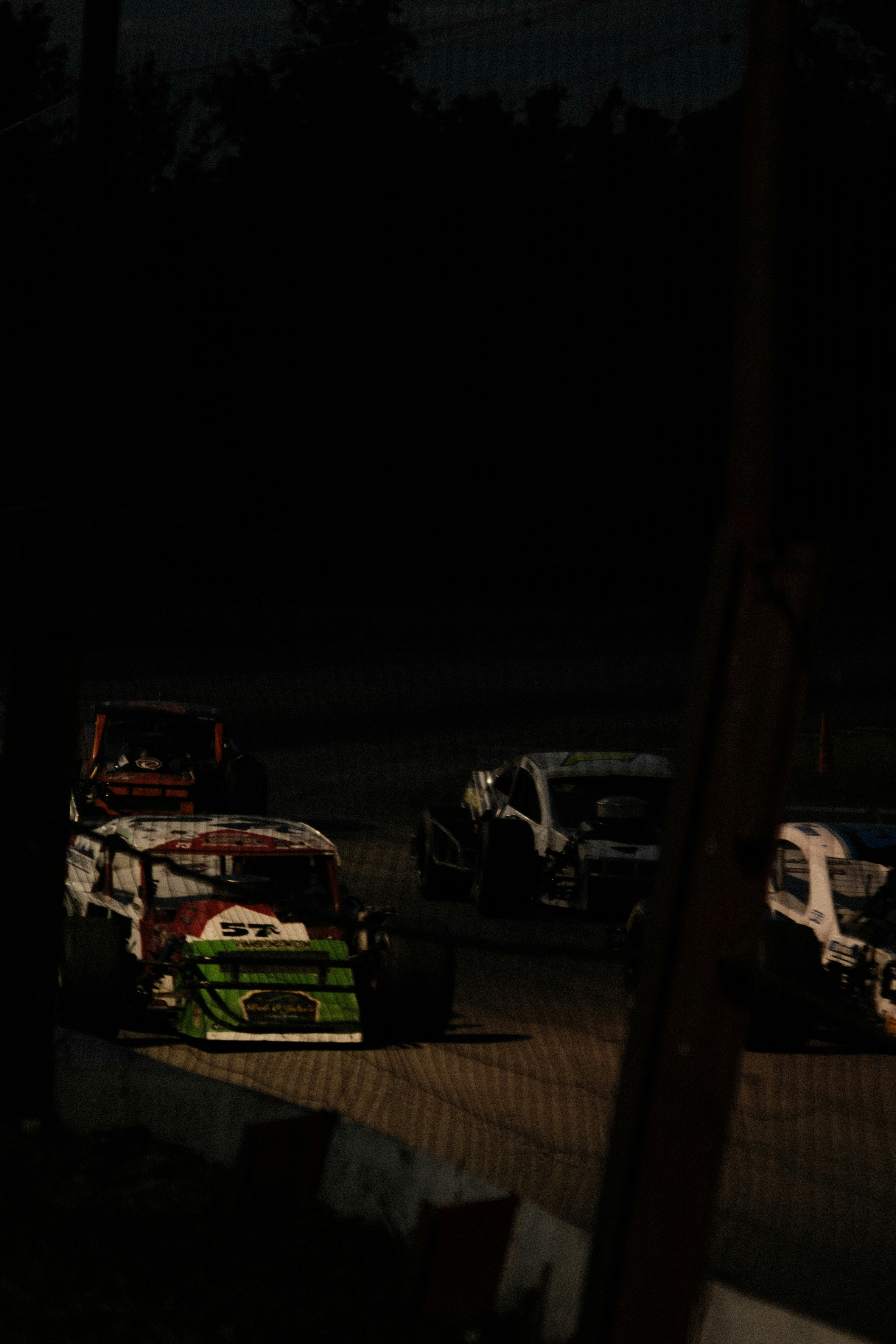 Speedway Shadows: A Pack of Race Cars Emerging from the Dark