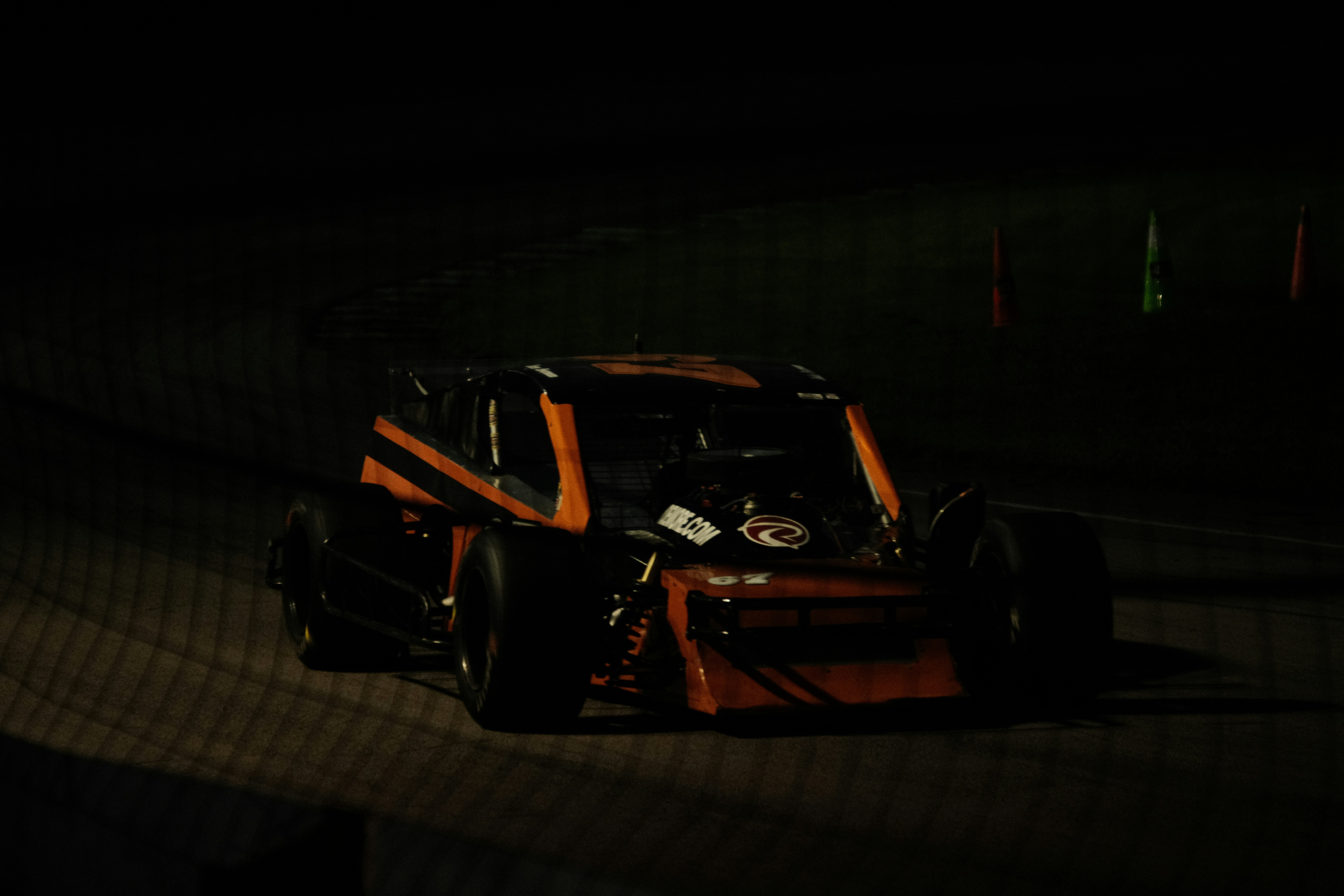 Midnight Racers: A solitary orange chassis carving the night on a dimly lit track