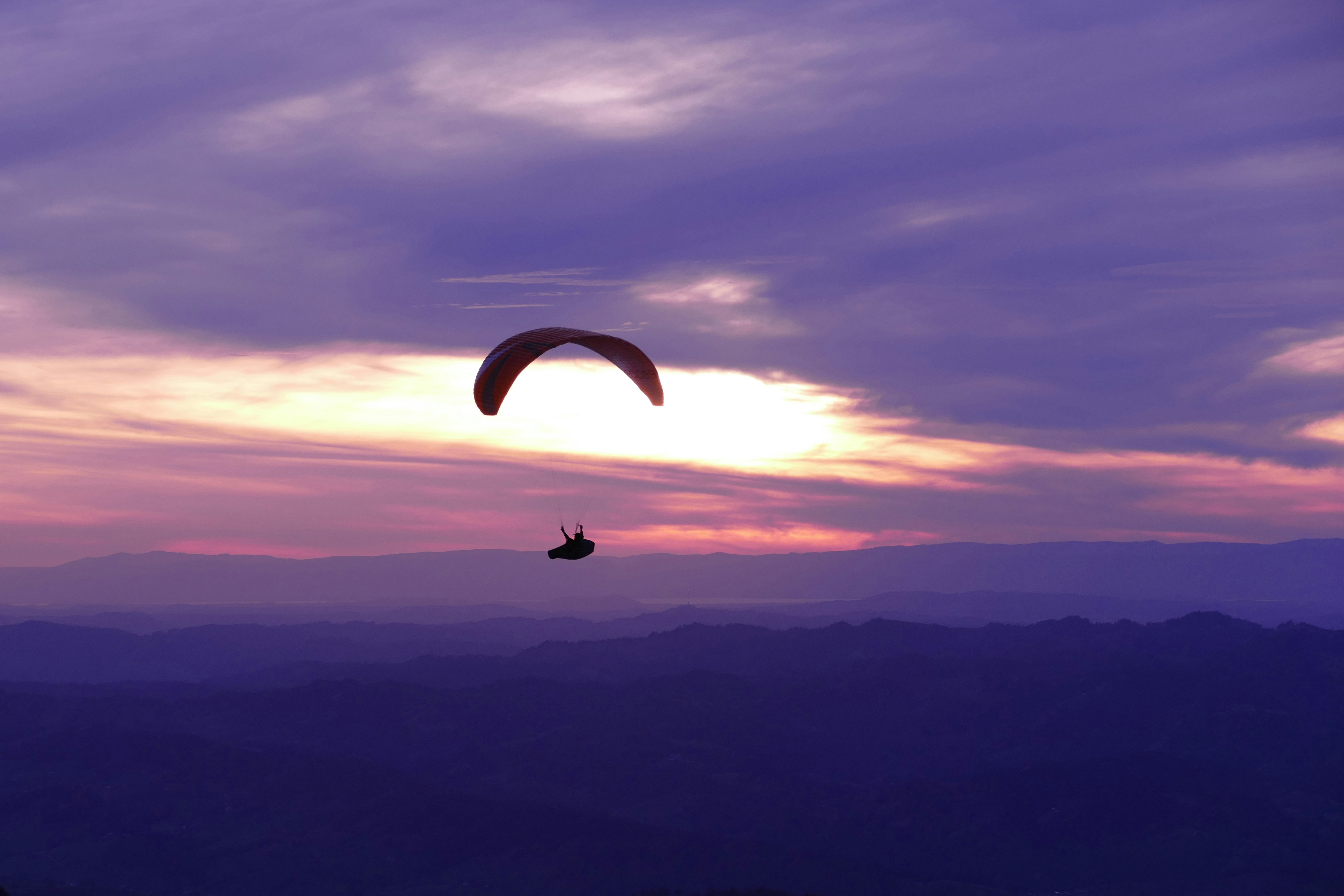Sunset Silhouette: Paraglider Above Dusky Ridge