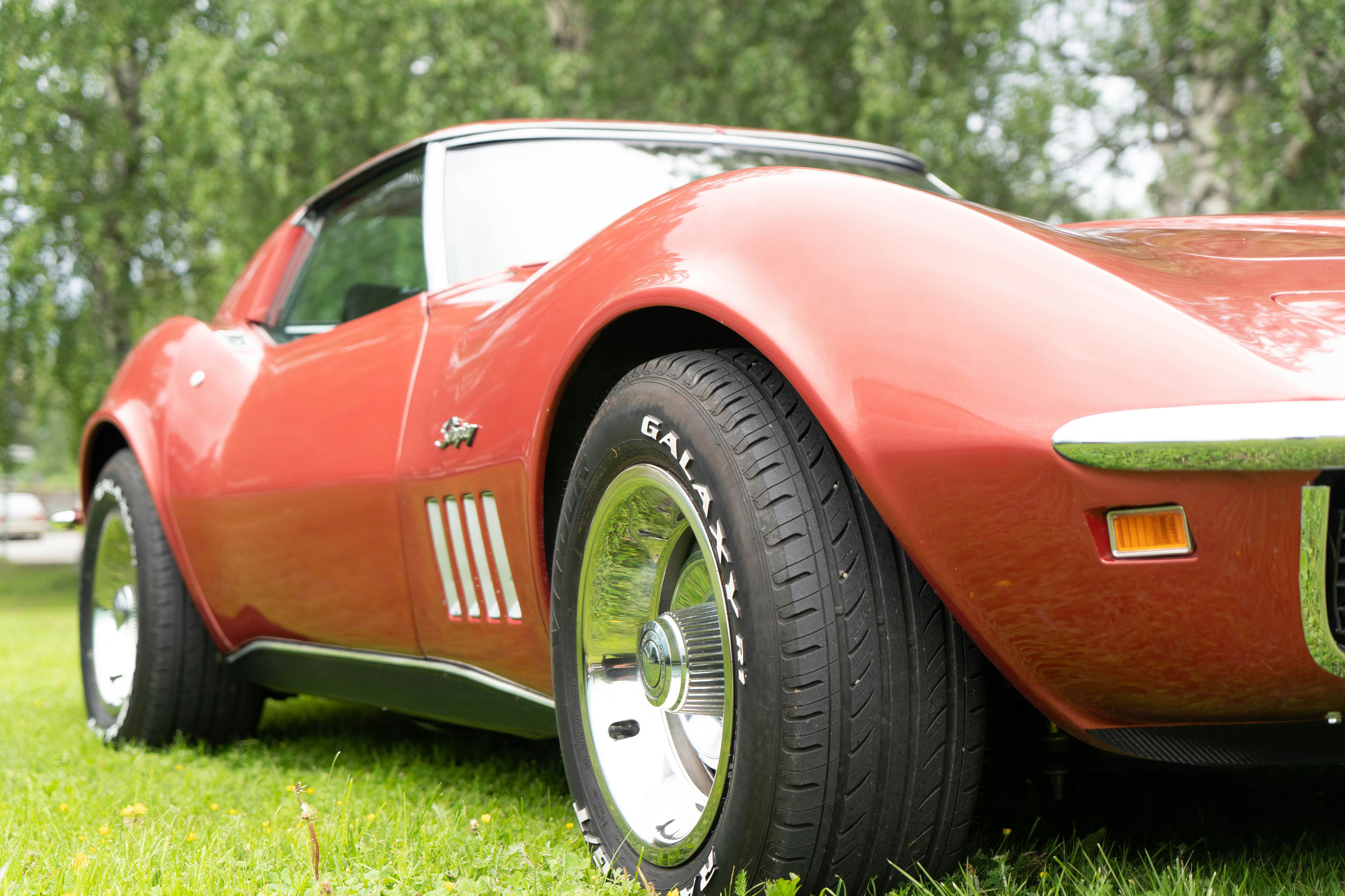 Glossy Red Classic: A Low Shot at a Muscle Car’s Wheelwell