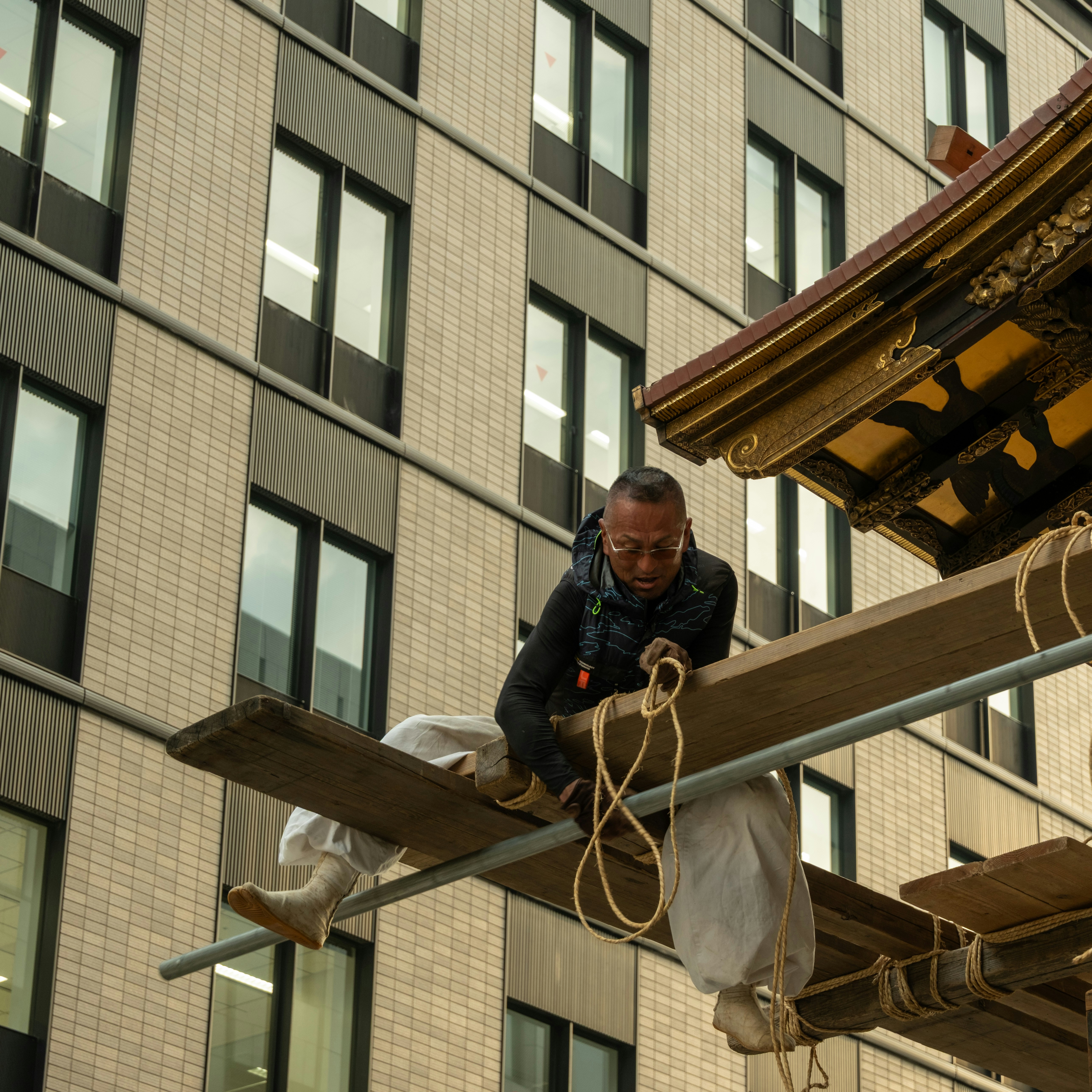 Climber on a Suspended Beam Amid City Glass Facade
