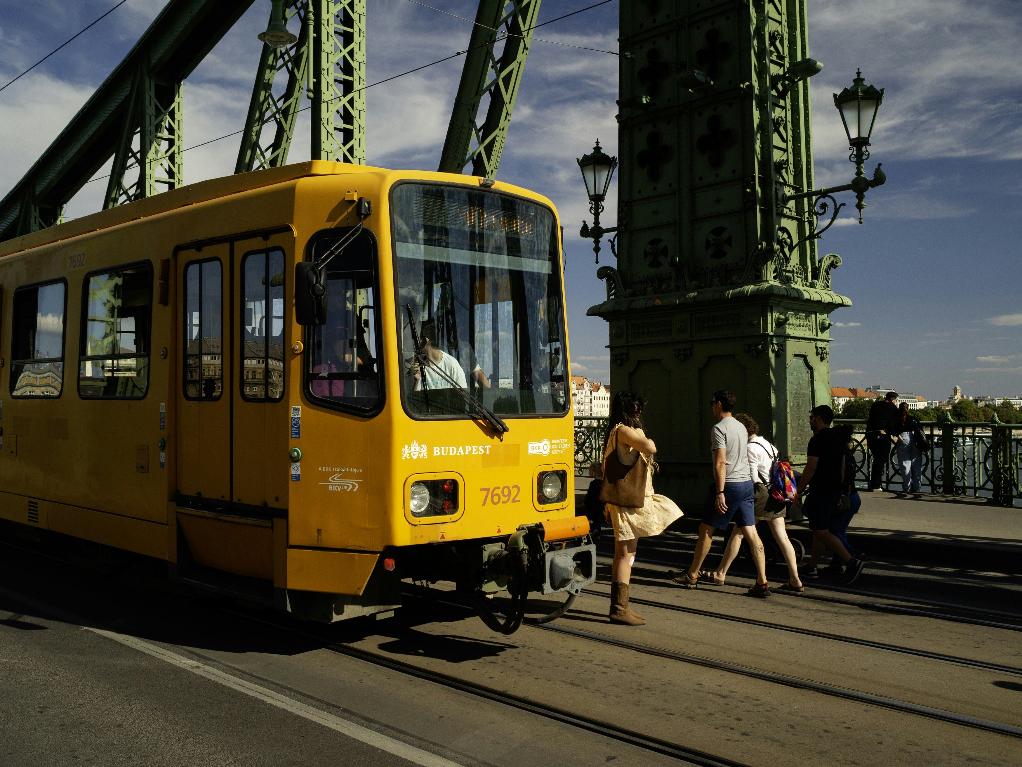 Yellow tram at the bridge: motion, structure, and passerby