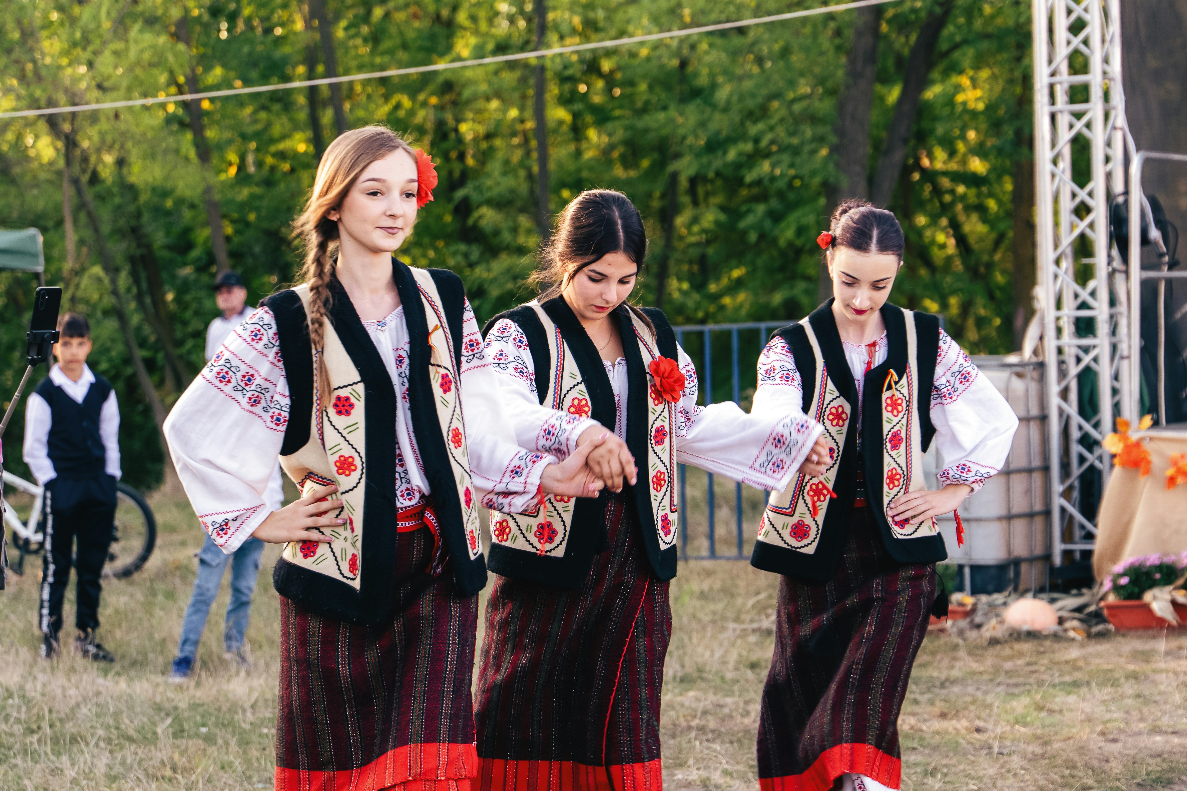 Three Dancers in Traditional Attire Share a Moment in a Sunlit Field