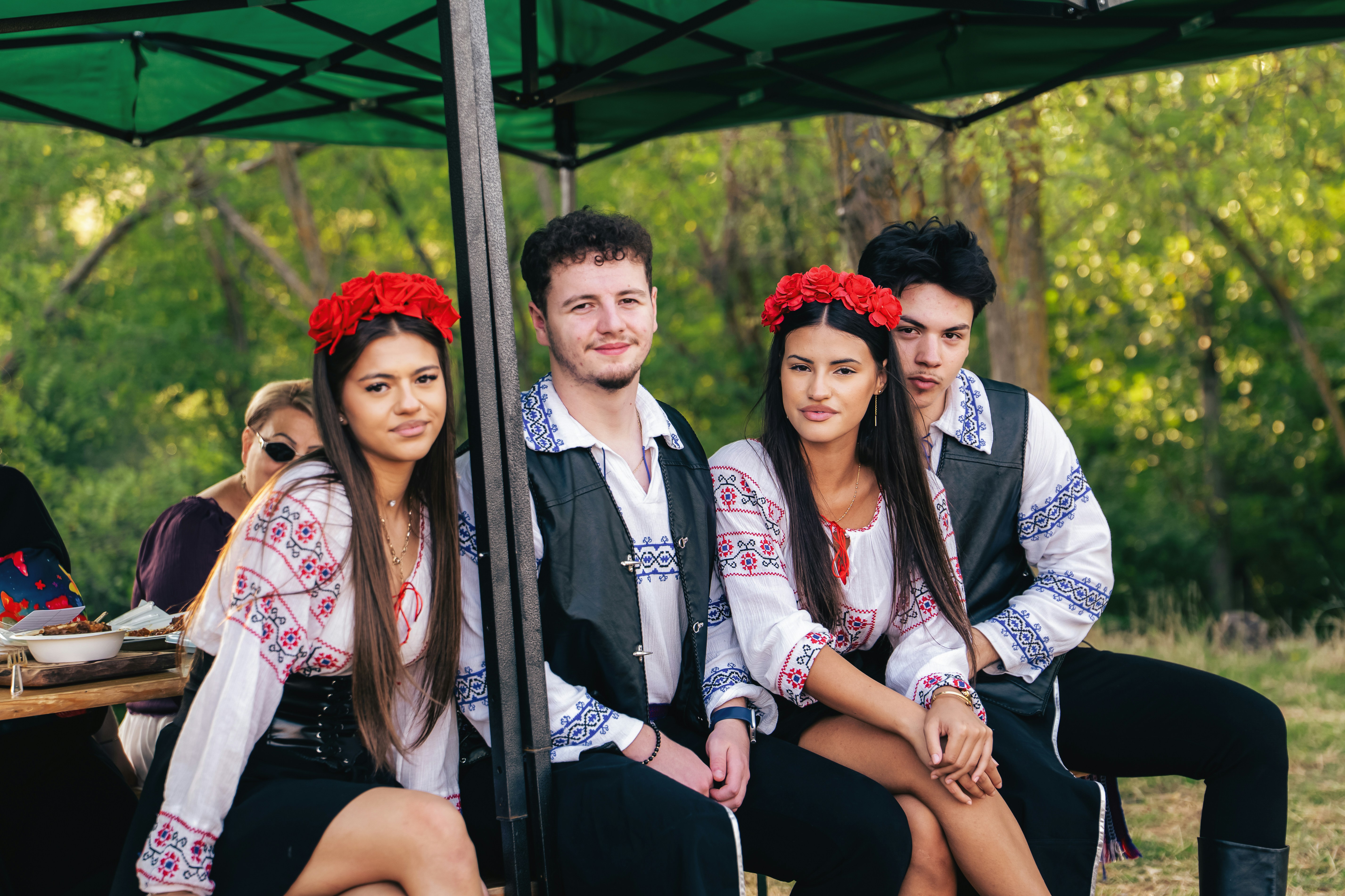 Festival Family: Four Friends in Traditional Attire Sharing a Moment Under a Green Canopy